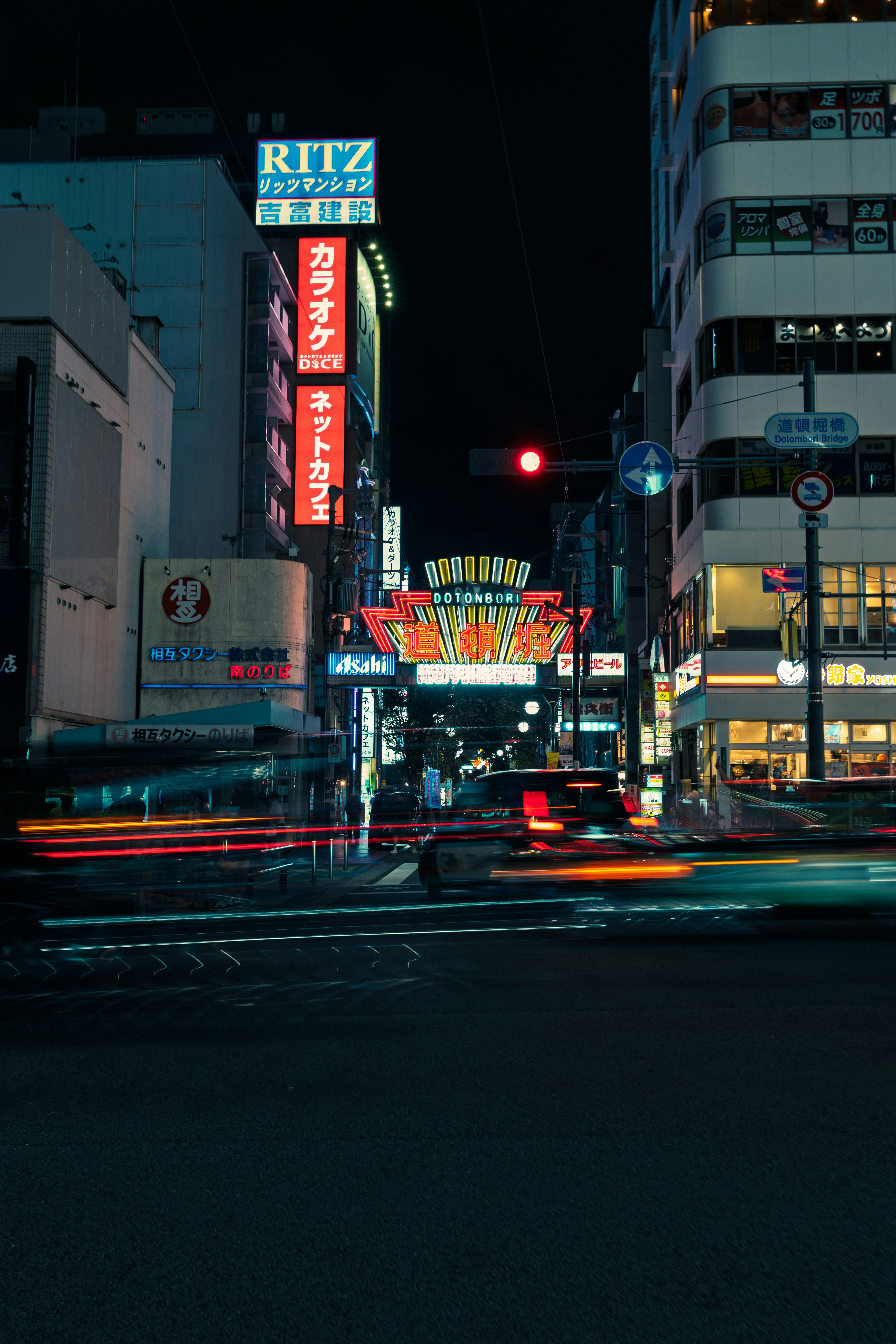 Neon signs illuminate a busy city street at night.