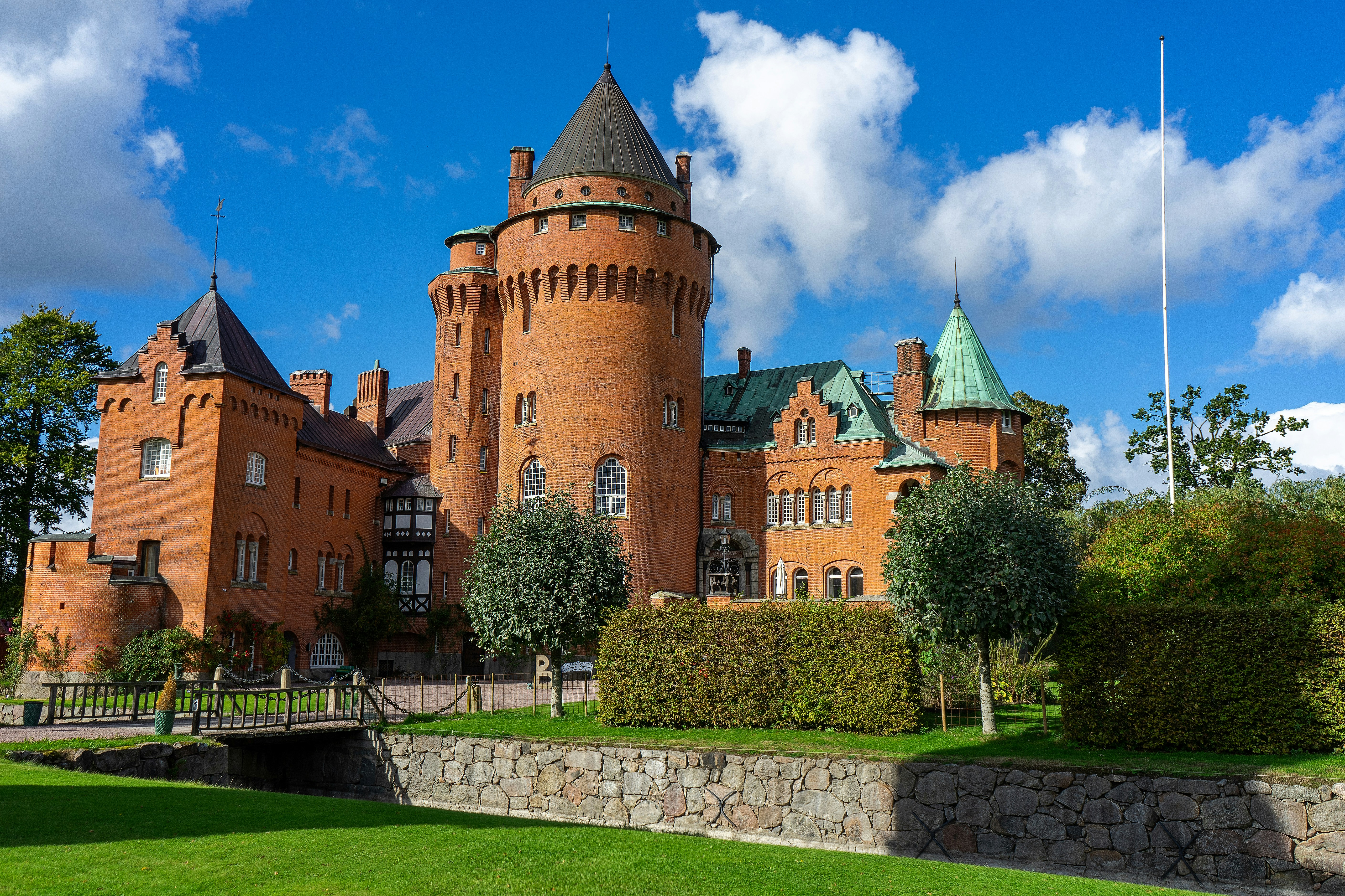 Hjularöd slot | A majestic brick castle with turrets under a blue sky.