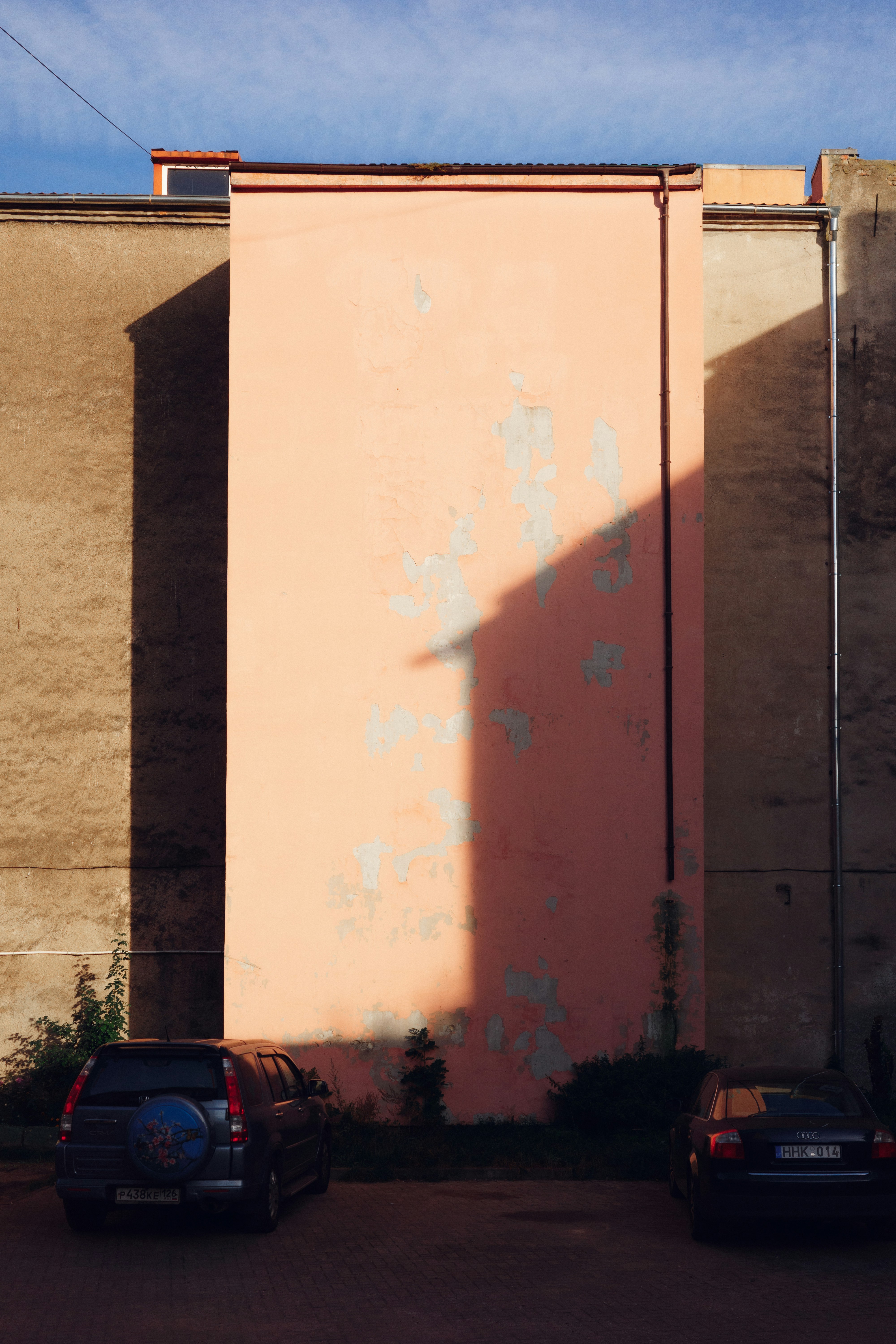 Two cars parked beside a peach-colored wall. photo – Free Car Image on ...