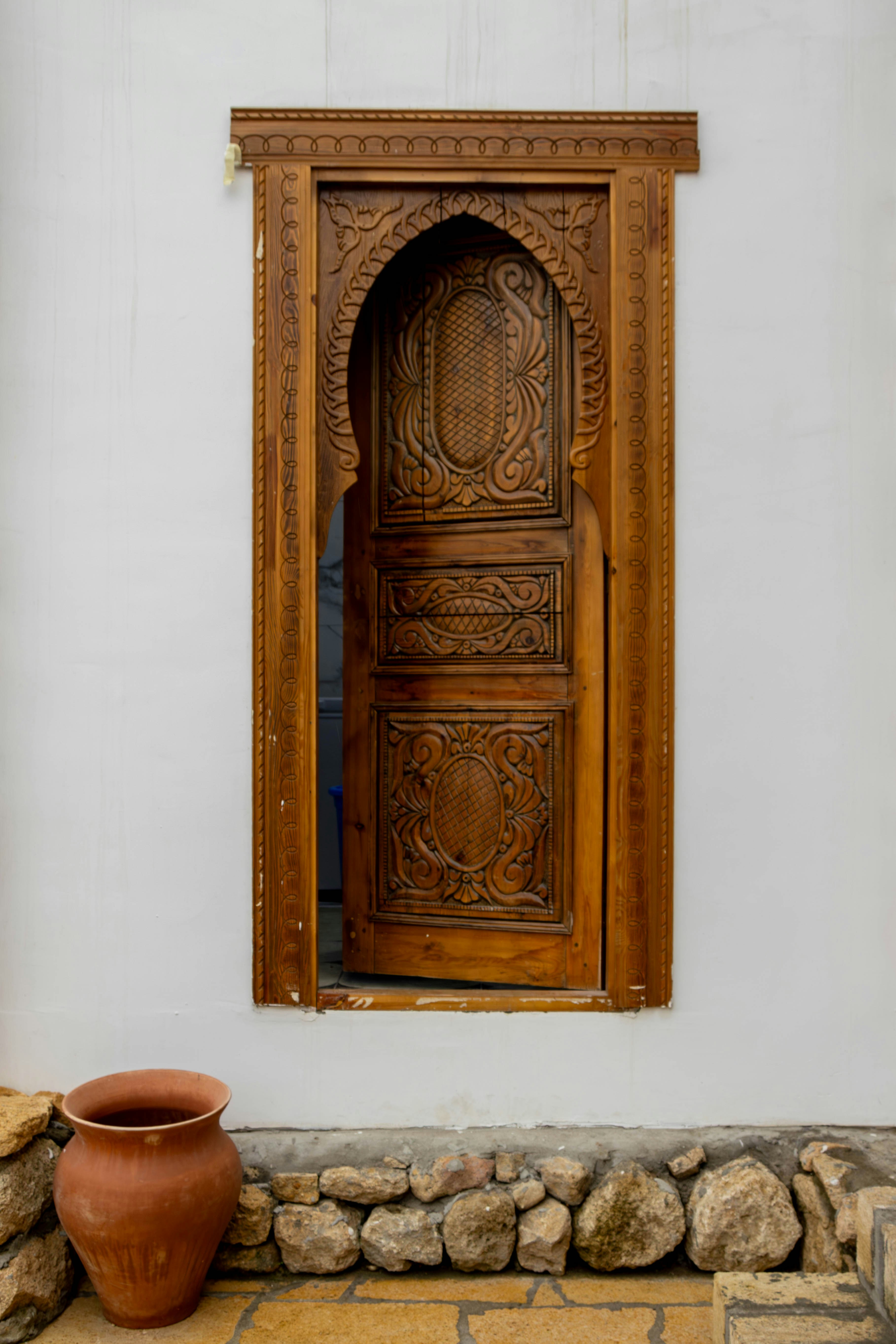Open door | Ornate carved wooden door with an arched opening.