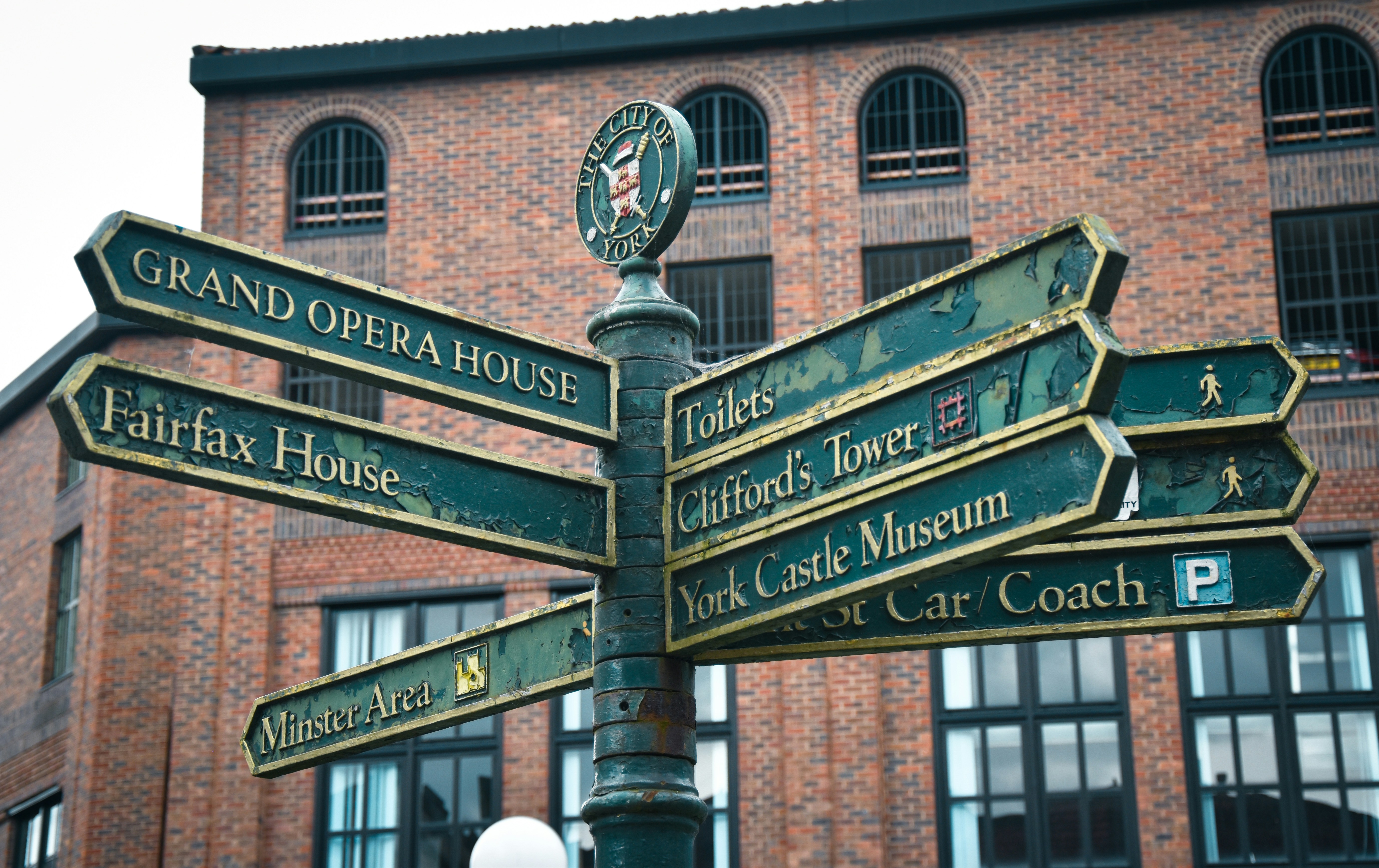 A sign in York City, England displaying popular tourist destinations including the Grand Opera House and York Castle Musuem. | Street signpost pointing to various city landmarks