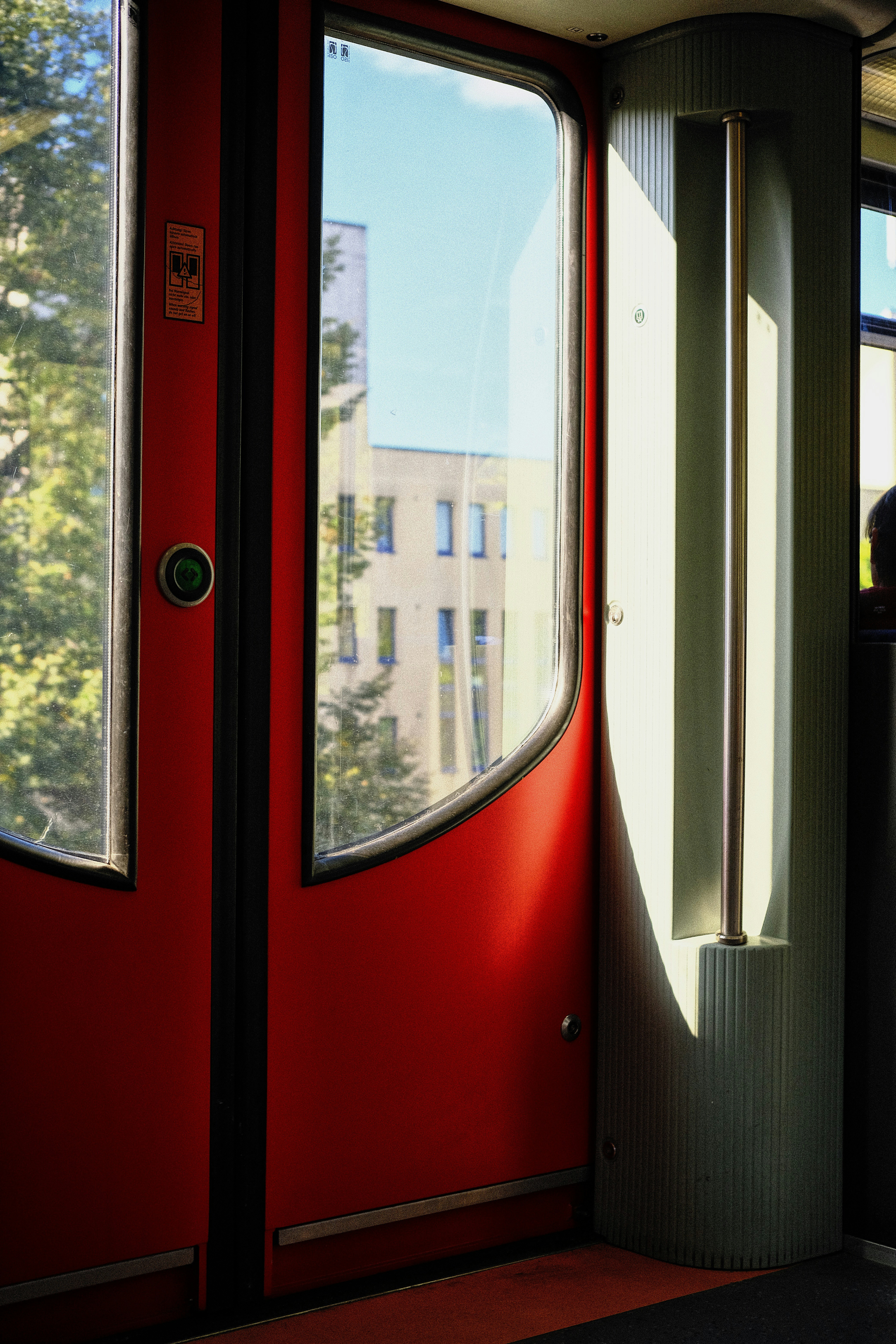 Red doors on a train with sunlight streaming in.