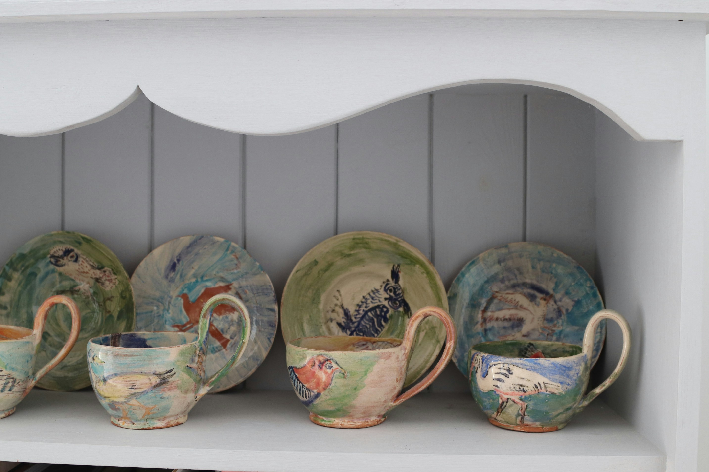 Collection of artistic ceramic cups and saucers on shelf