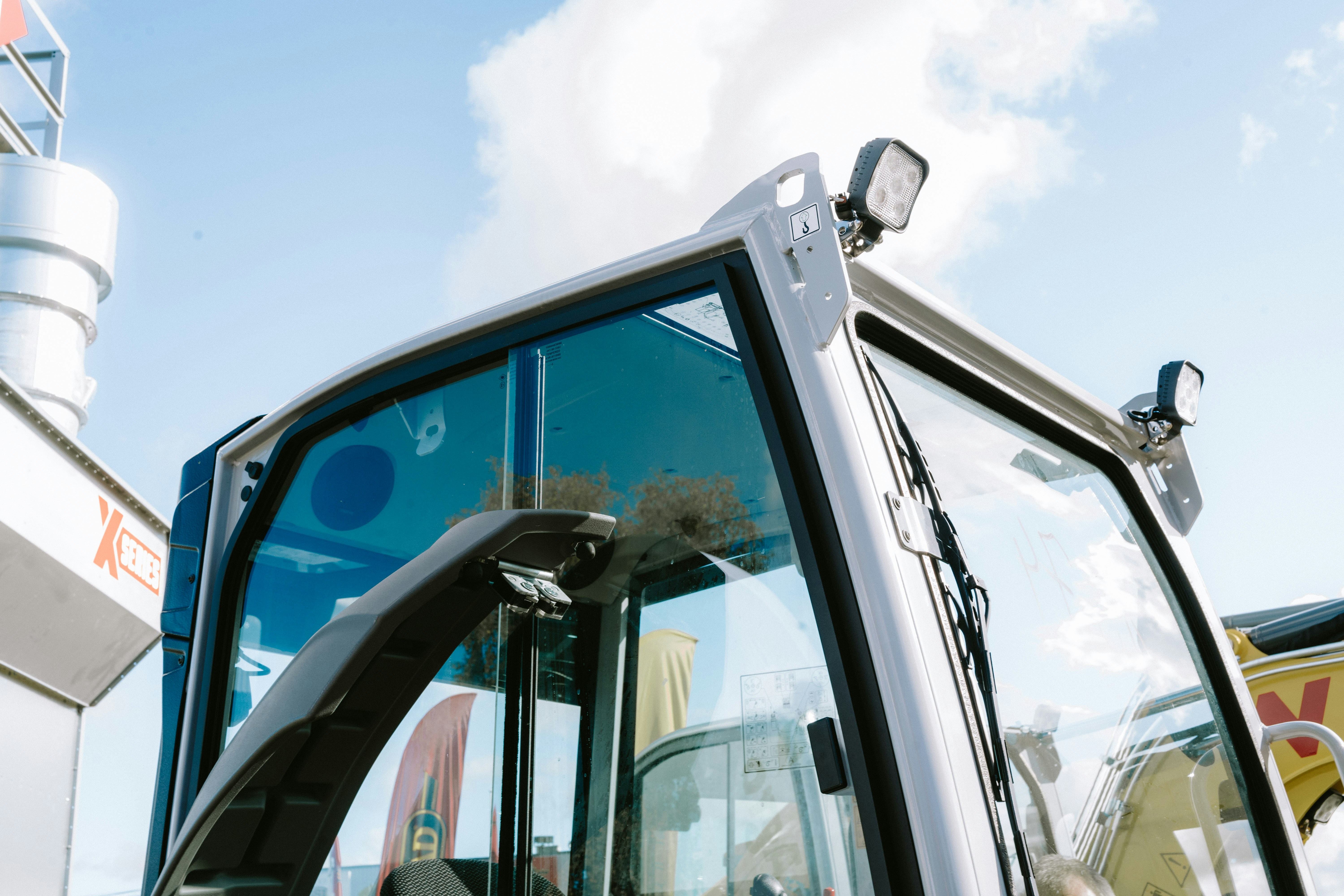 Close-up of Excavator Cab Roof and Glass Windows in Construction Machinery | Close-up of a modern excavator cabin under blue sky