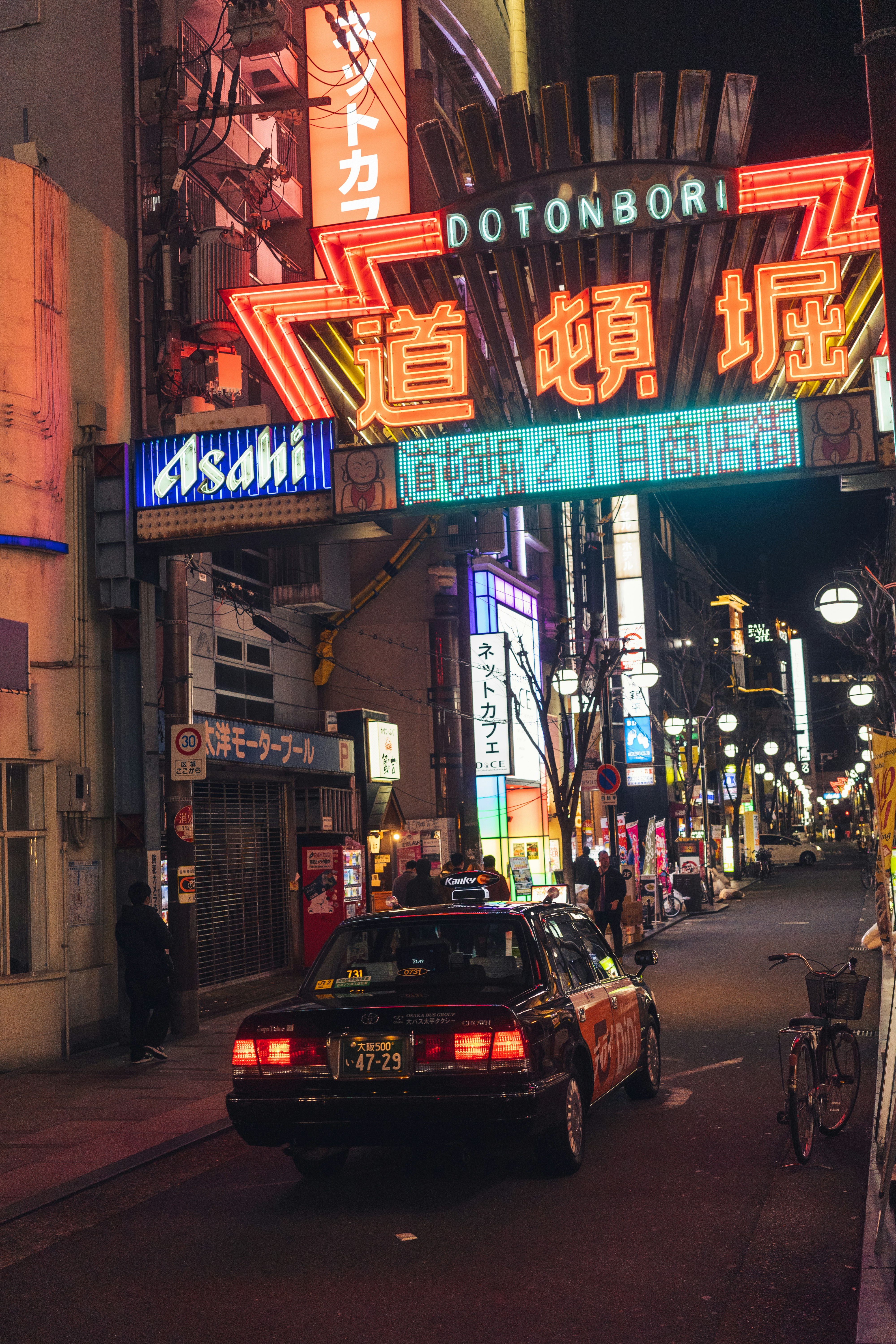 Neon signs illuminate a street in dotonbori, osaka at night.