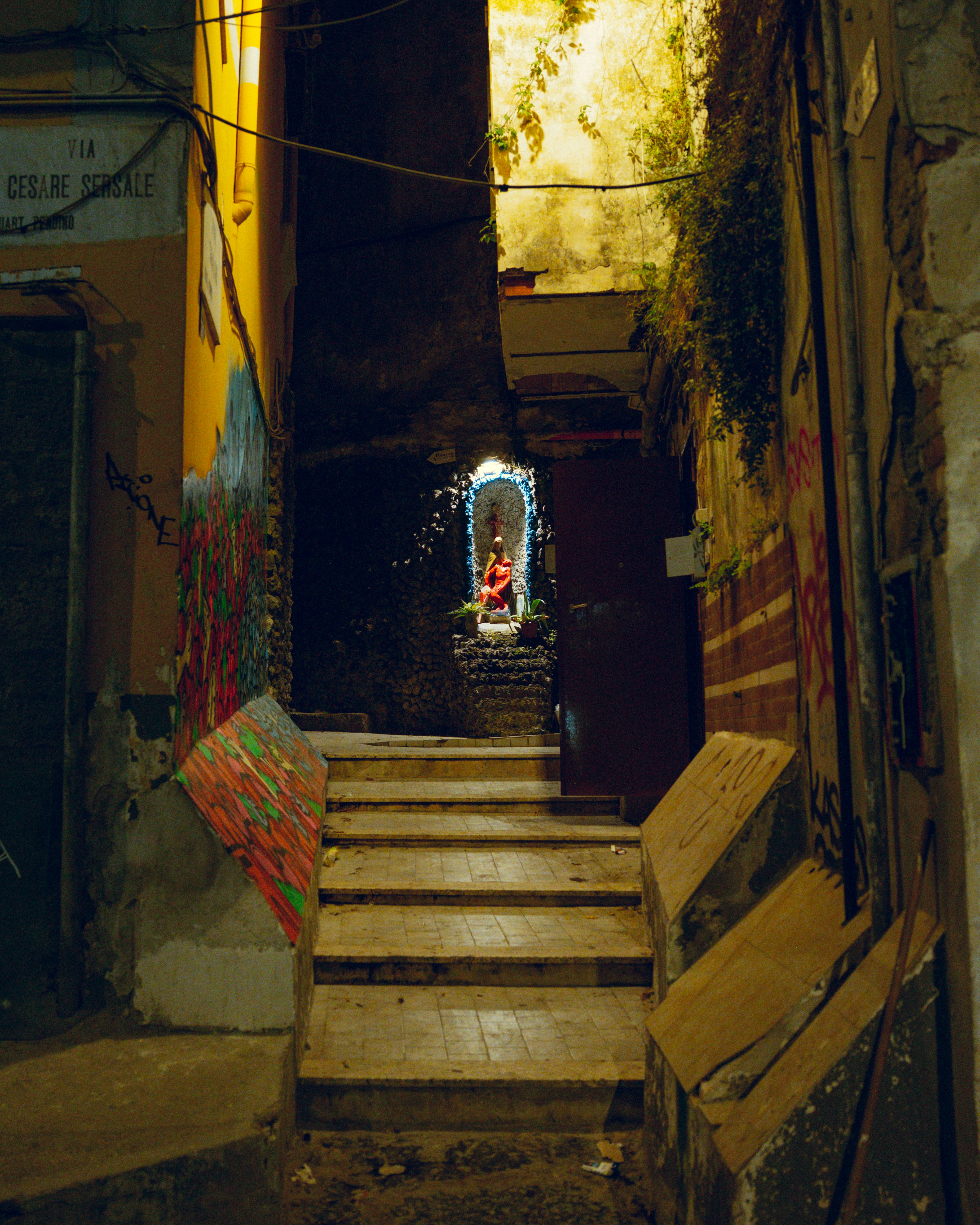 Narrow alleyway with stairs and a small shrine.