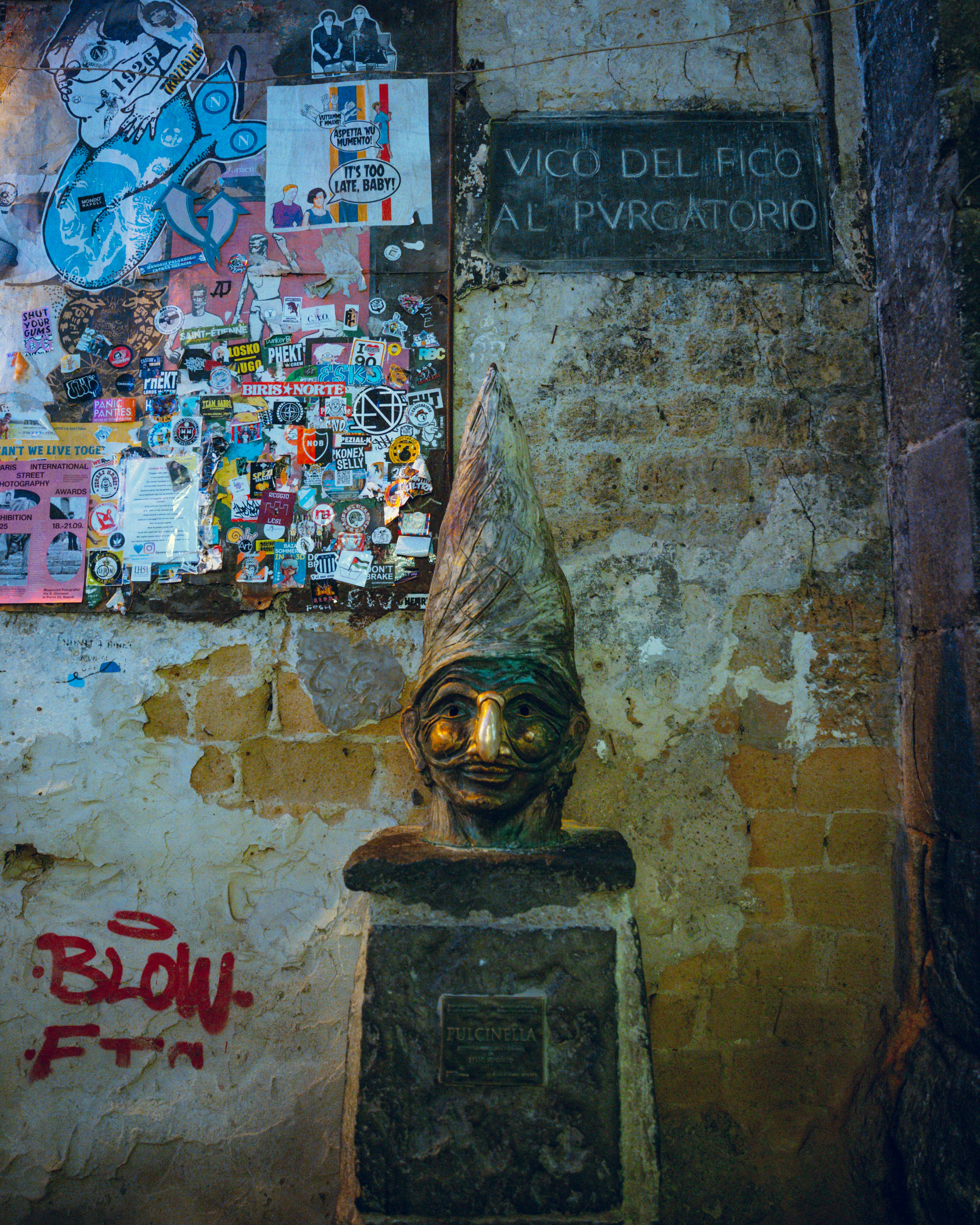 The Alley Gnome: Bronze Face Amid Posters and Graffiti