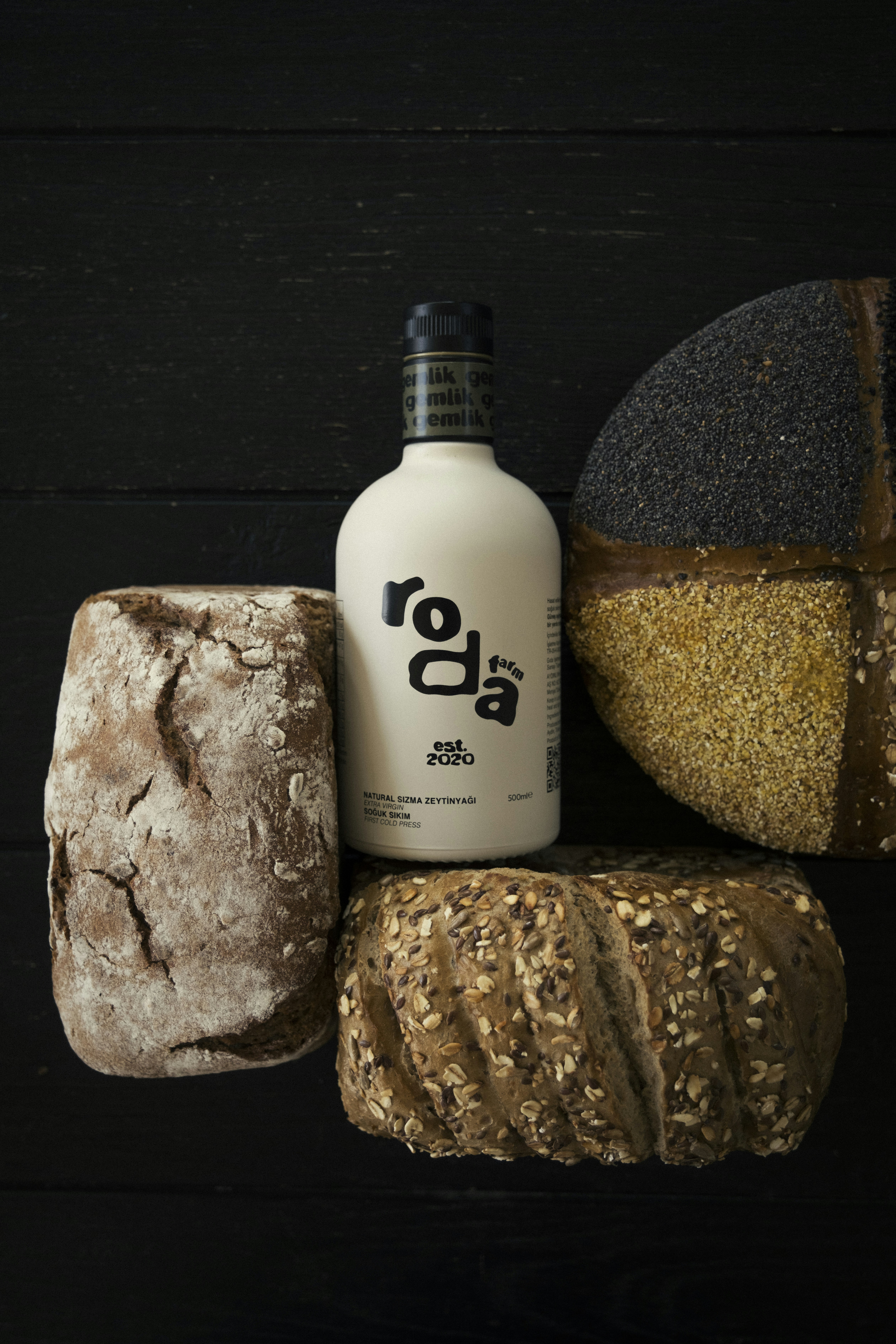Bottle of olive oil with artisan breads on dark background