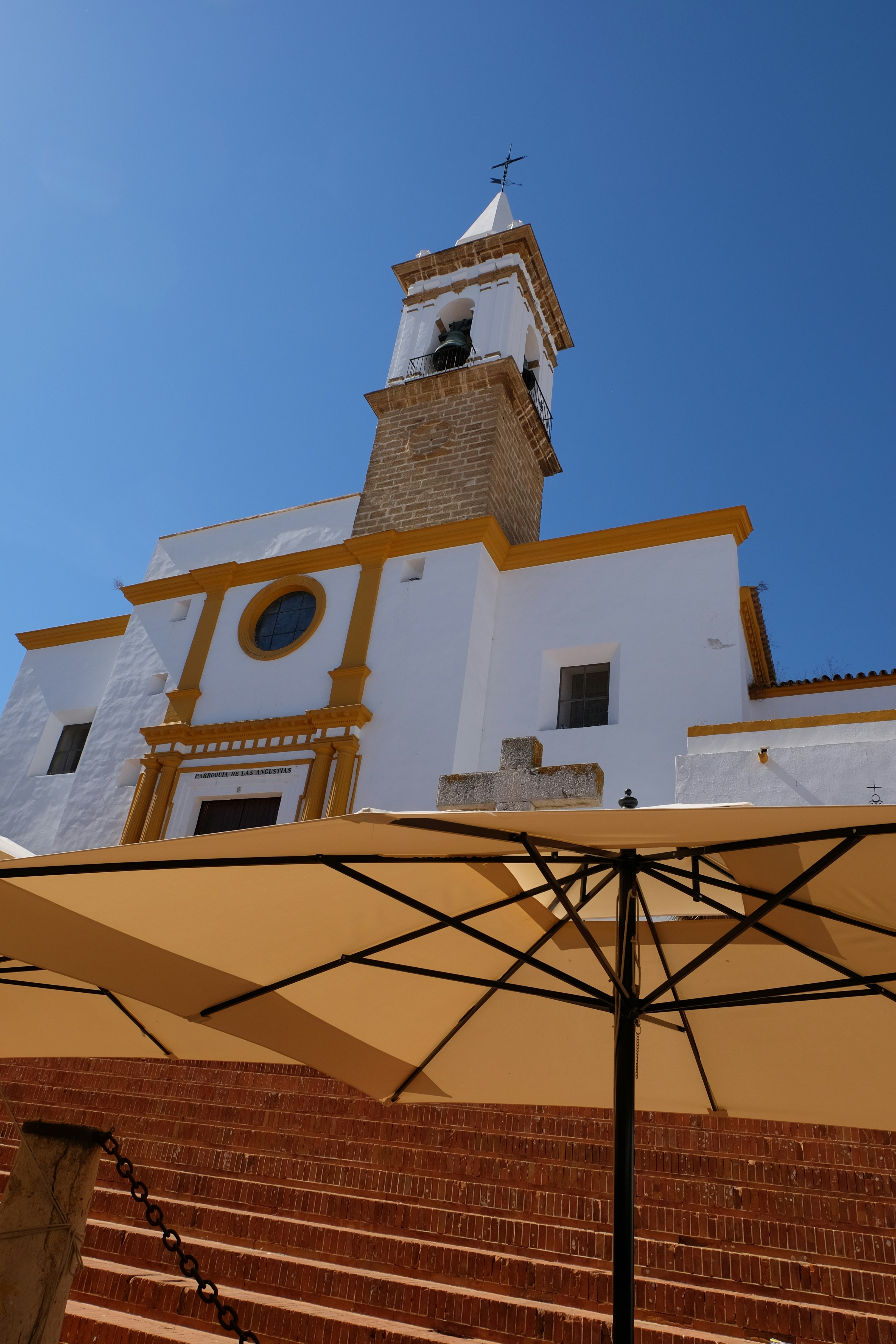 Amber-Trimmed Bell Tower Framed by White Walls Beneath a Pure Blue Sky