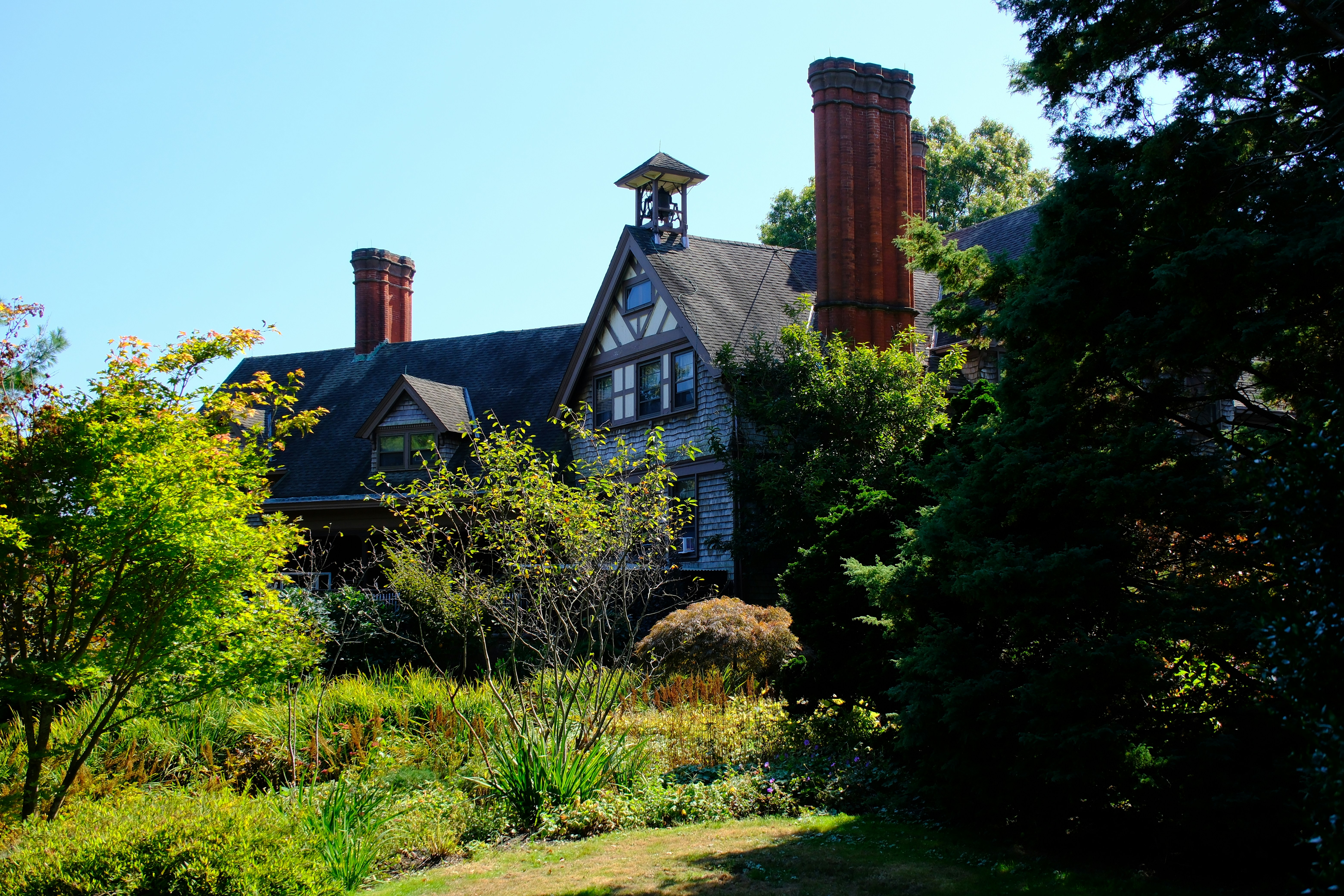 mansion in background surrounded by trees and grass in foreground