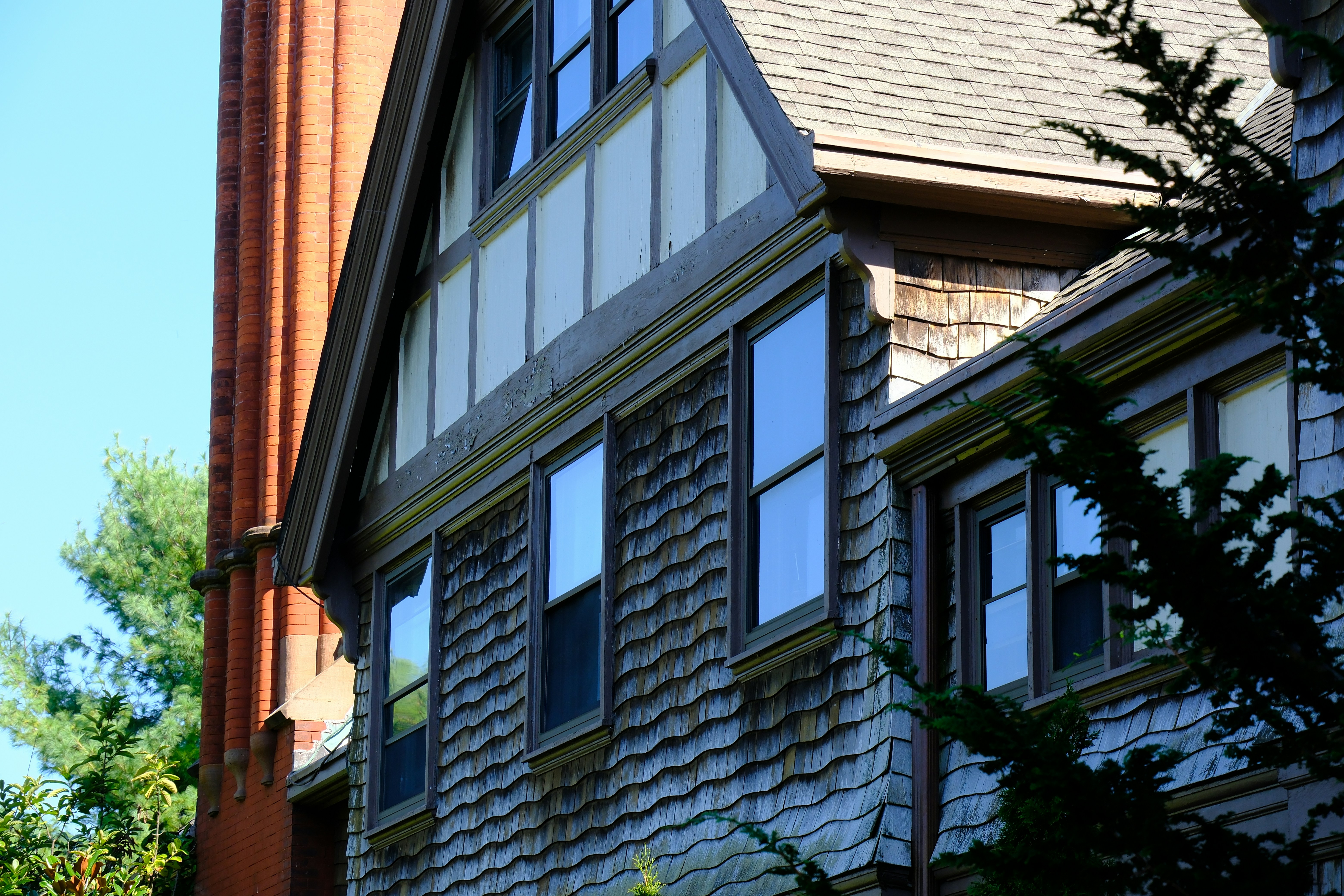 facade of mansion with three windows | A historic tudor-style house with shingled walls.