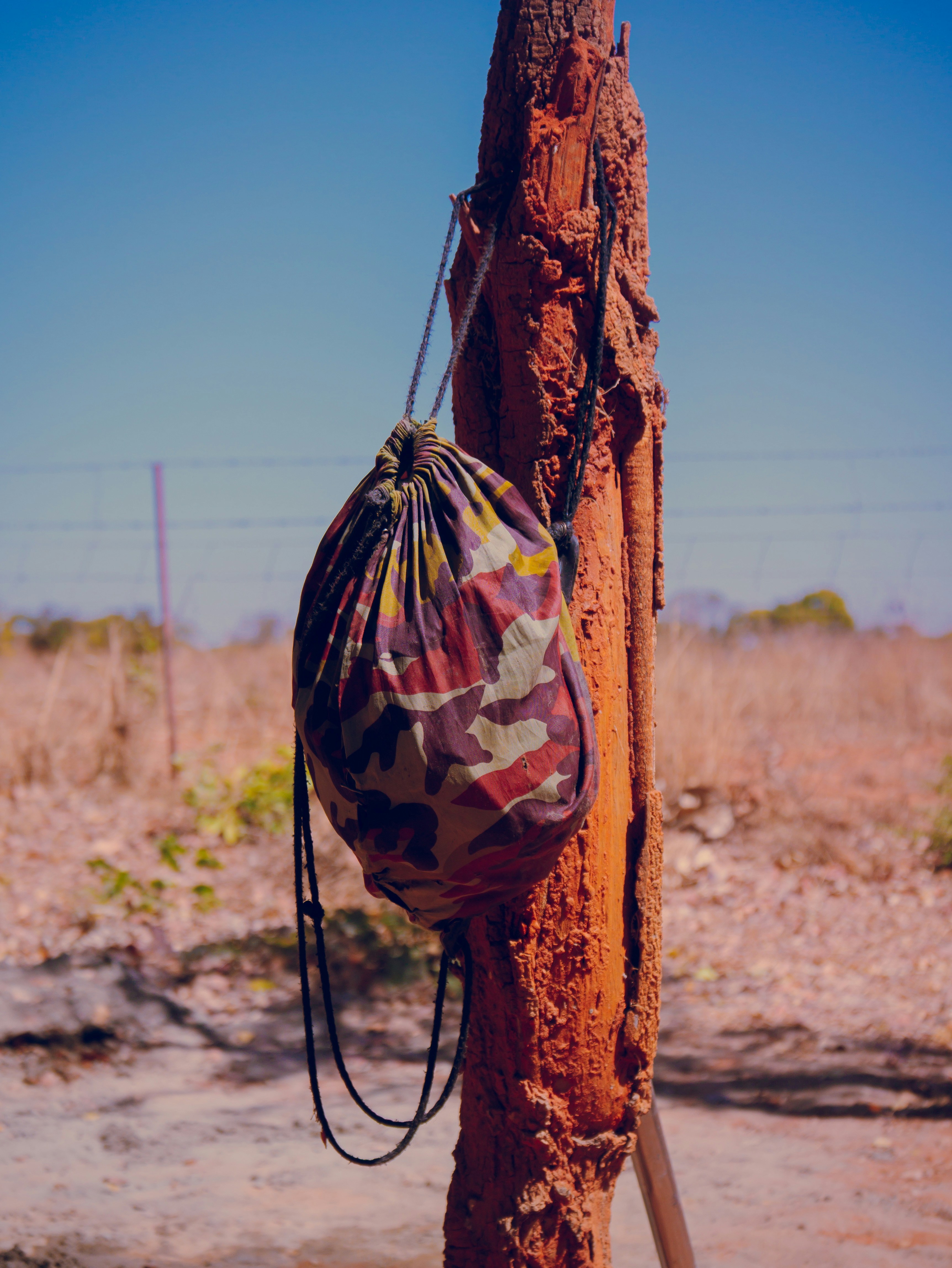 A camouflage drawstring bag hangs on a tree.