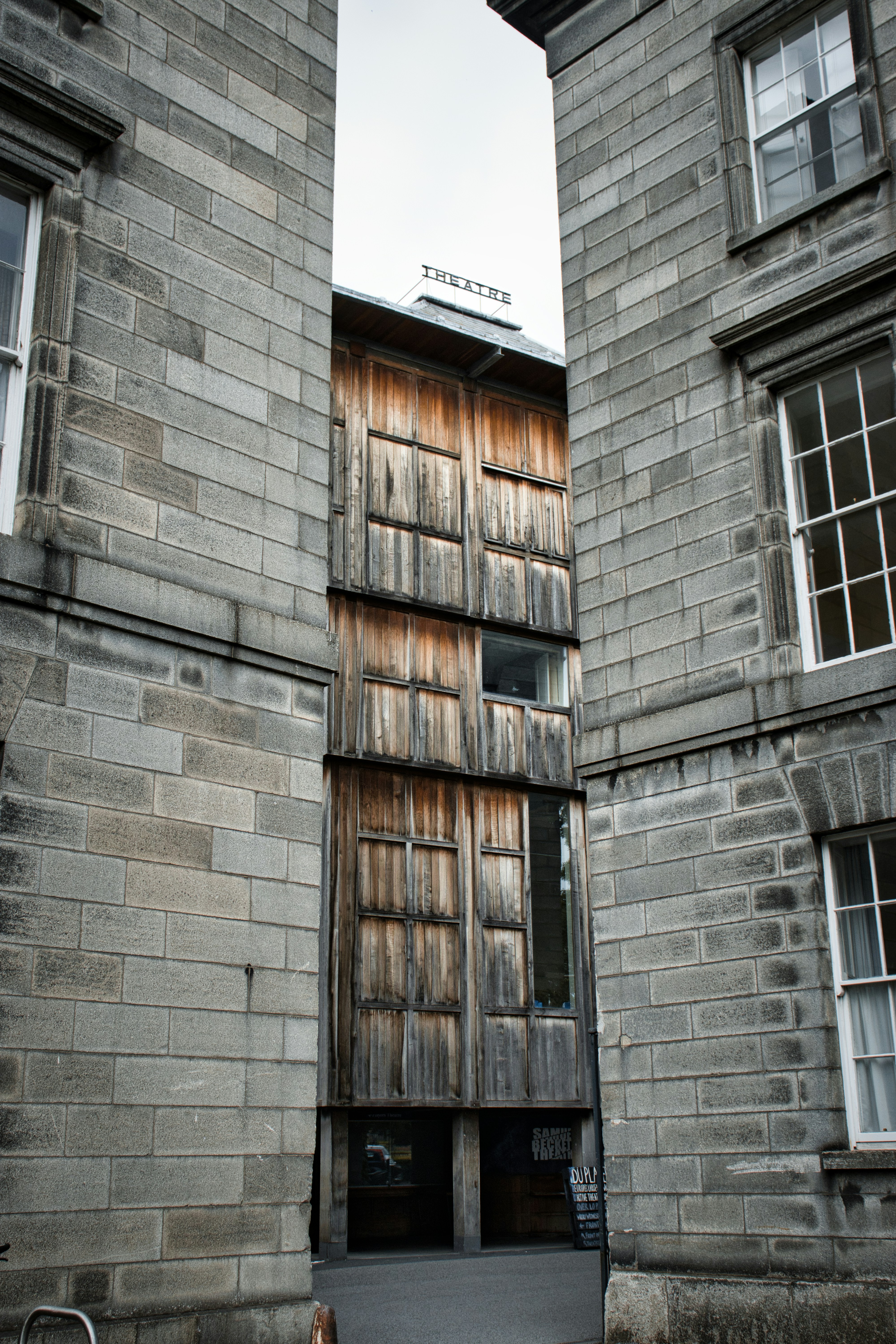Modern wooden building between stone structures
