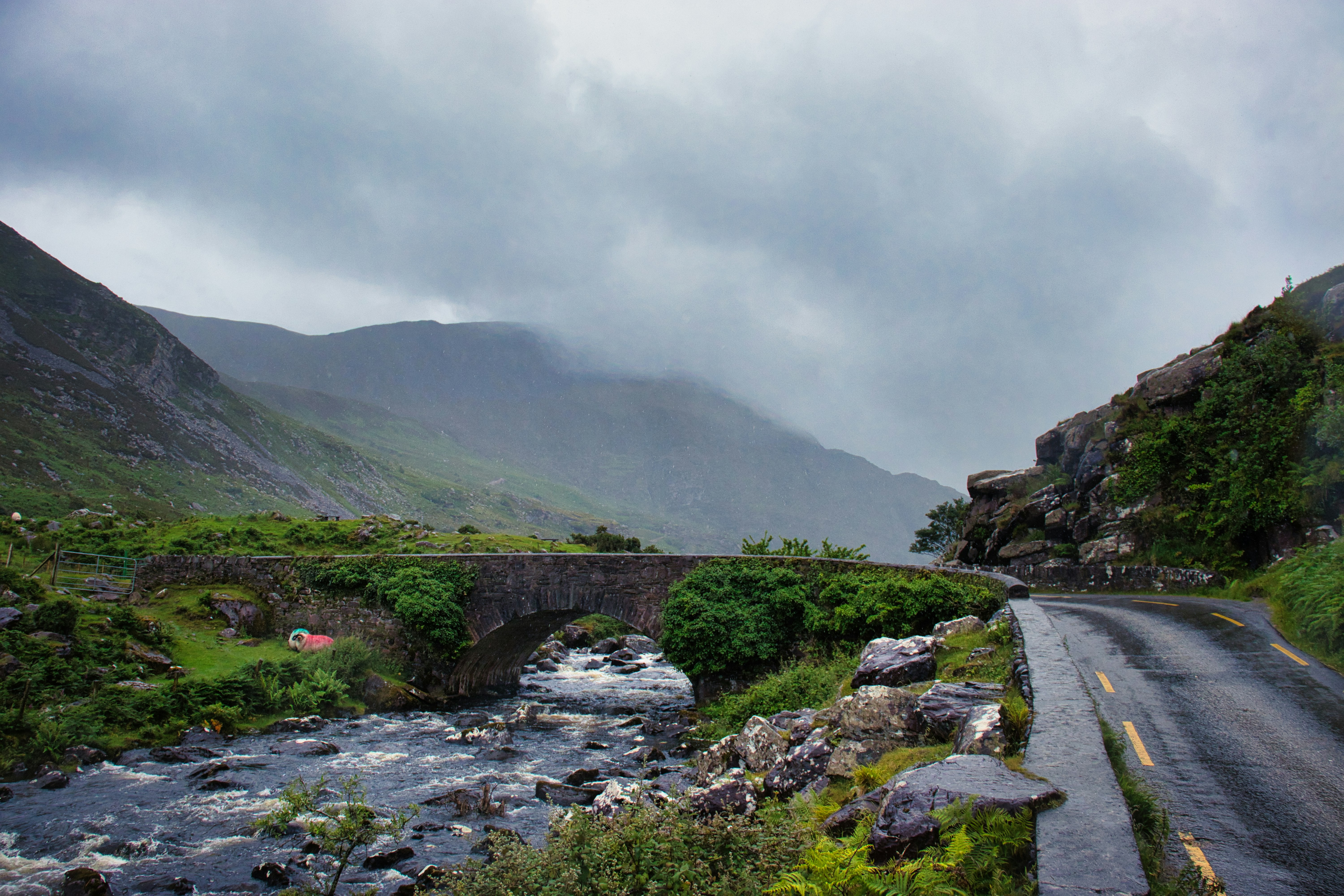 Misty Valley Bridge: Road, River, and Rock Converge Under Cloudy Skies