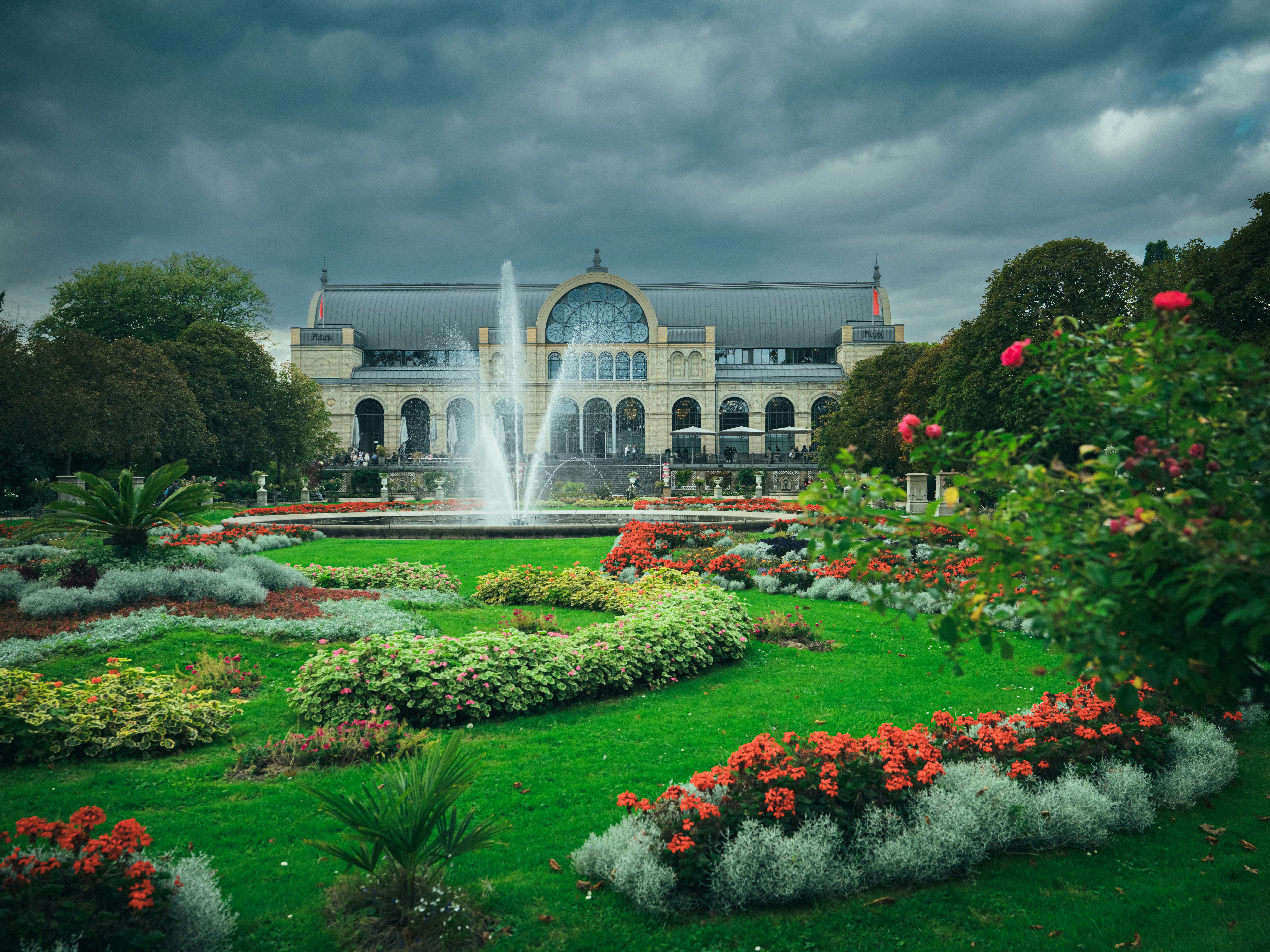 Flora Park Köln | Fountain in a formal garden with a building behind.