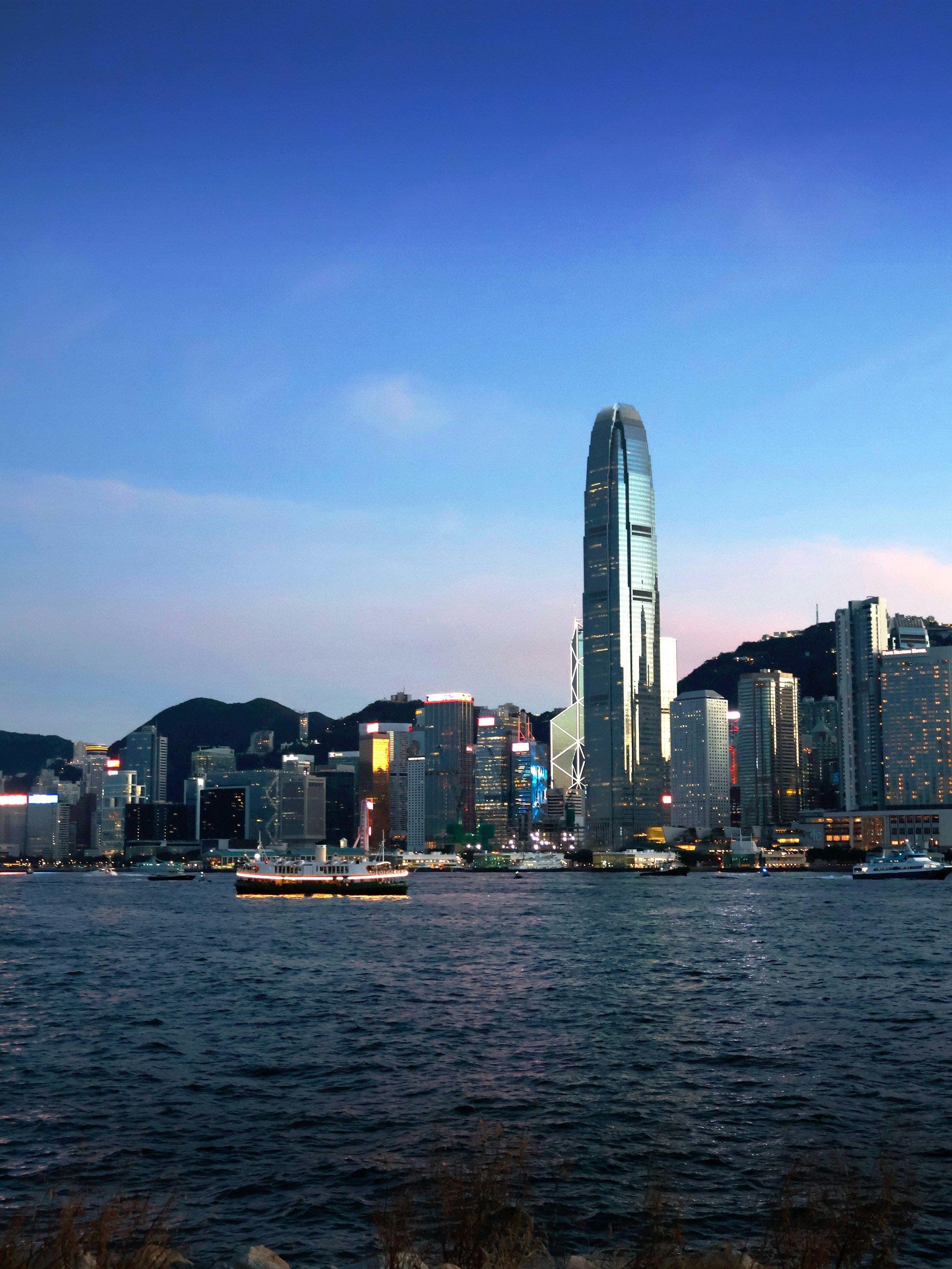 Modern cityscape with skyscrapers and a boat on water.