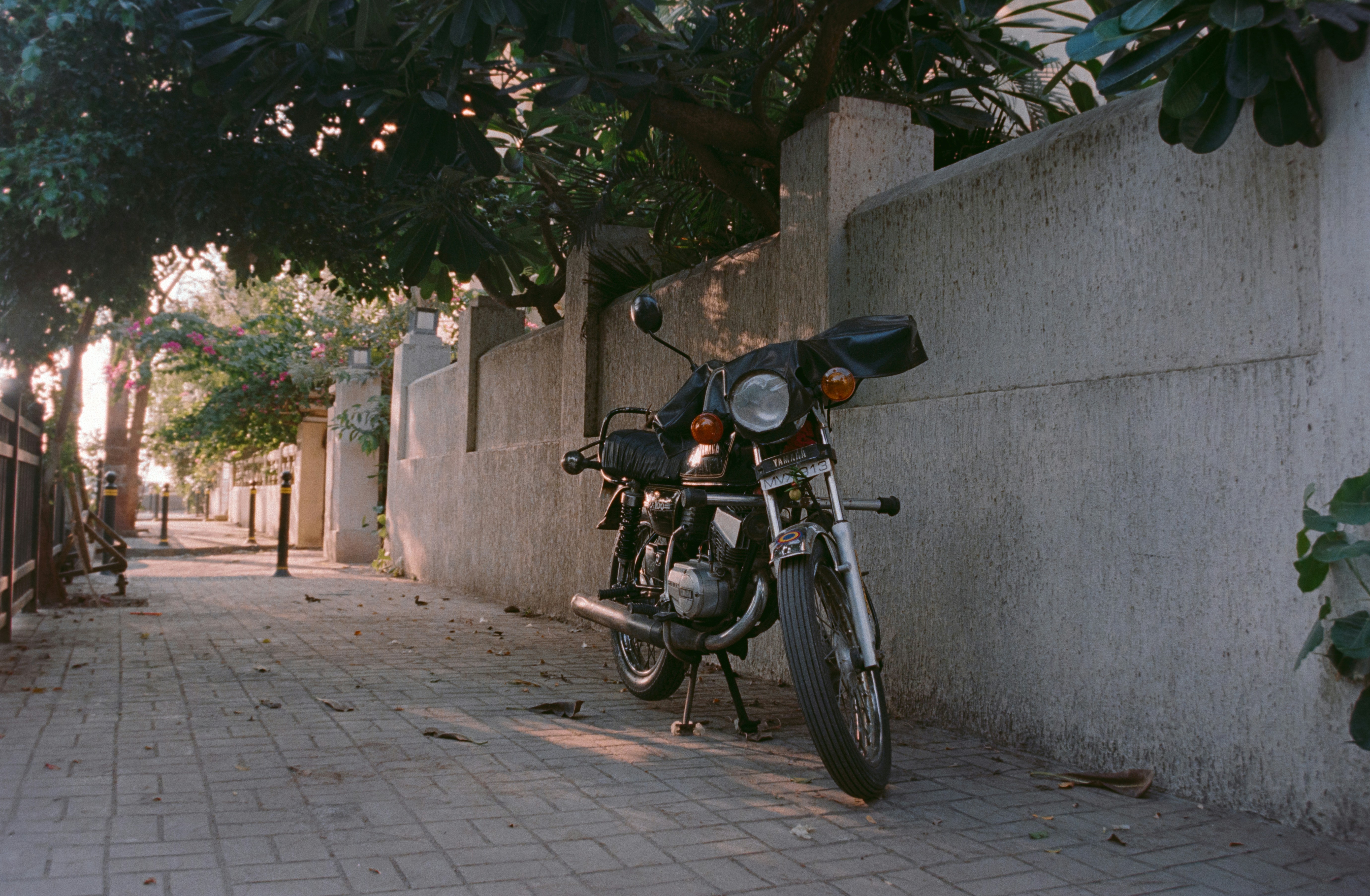 Motorcycle parked on a paved walkway near a wall.