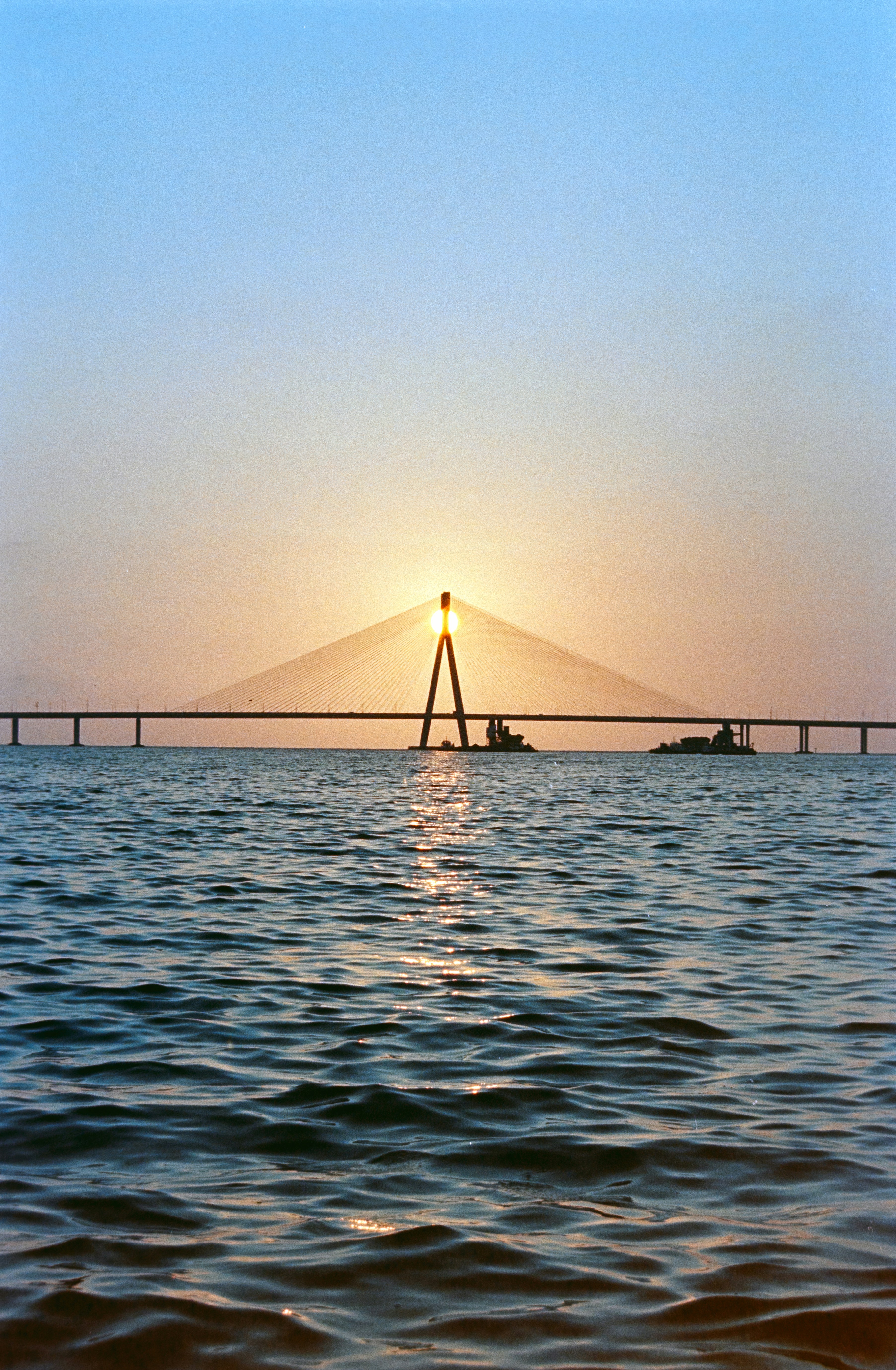 Apex in Light: Cable-Stayed Bridge at Sunset Over Quiet Sea