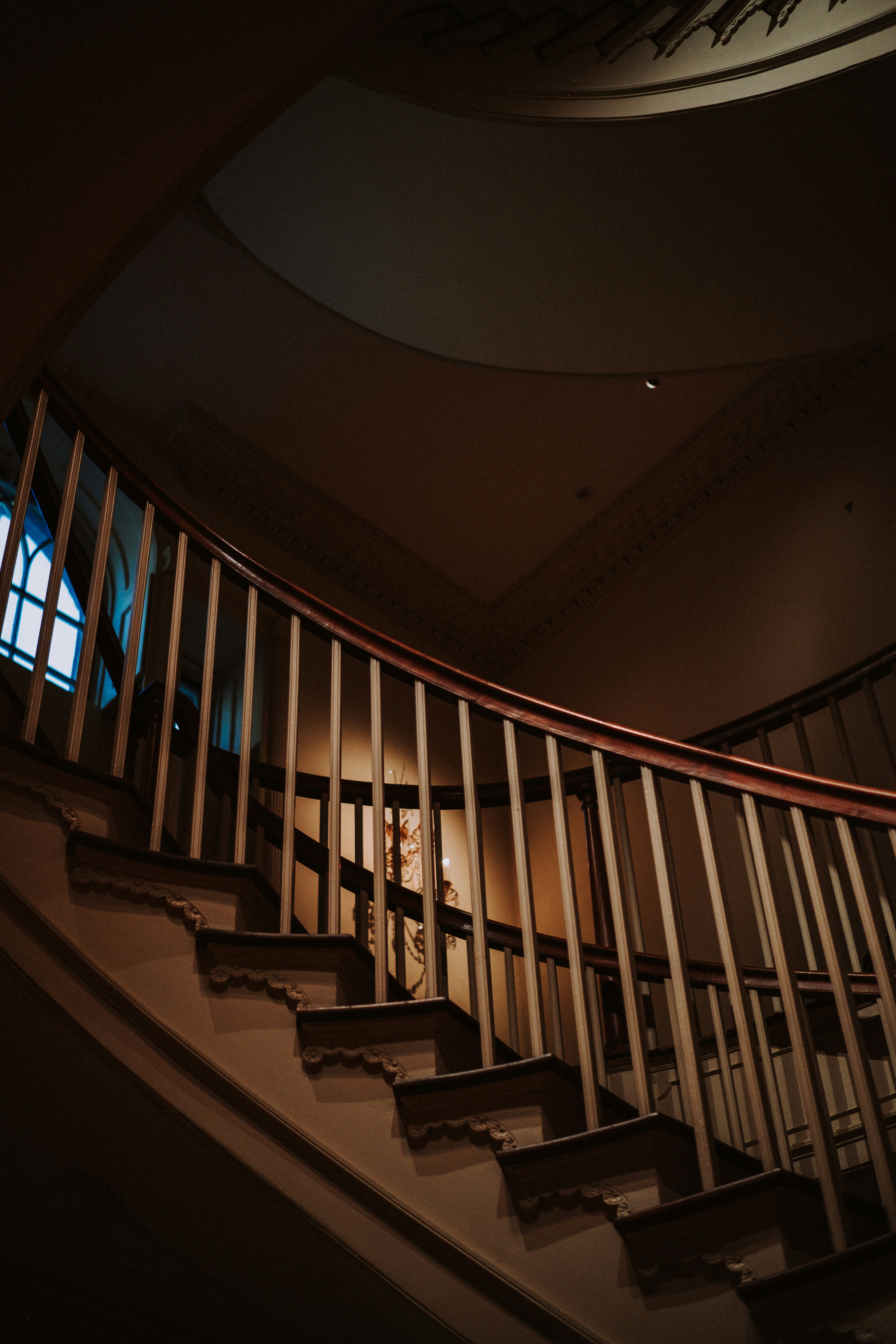 Curving staircase with ornate railing and window.