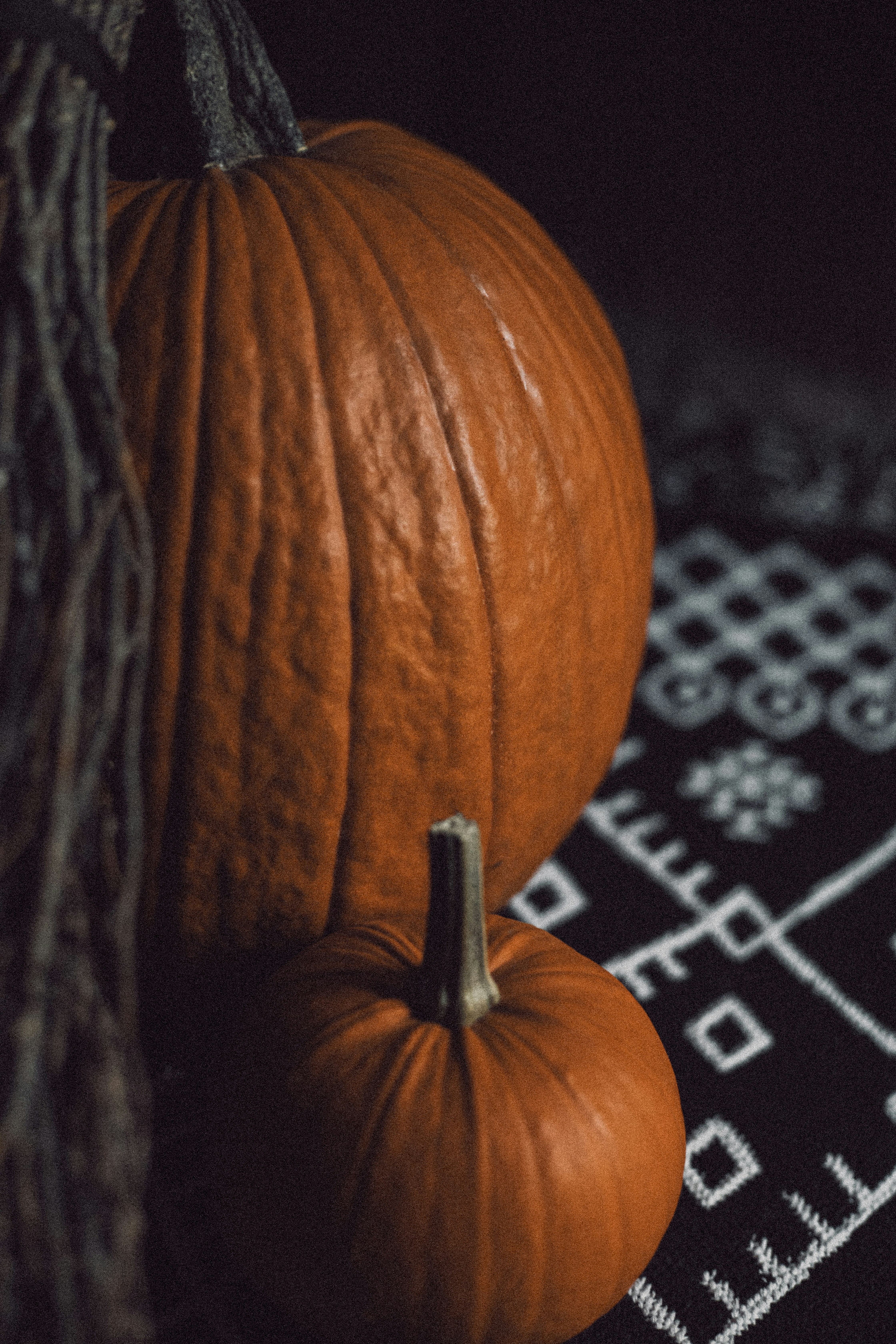 Two pumpkins sit on a patterned rug