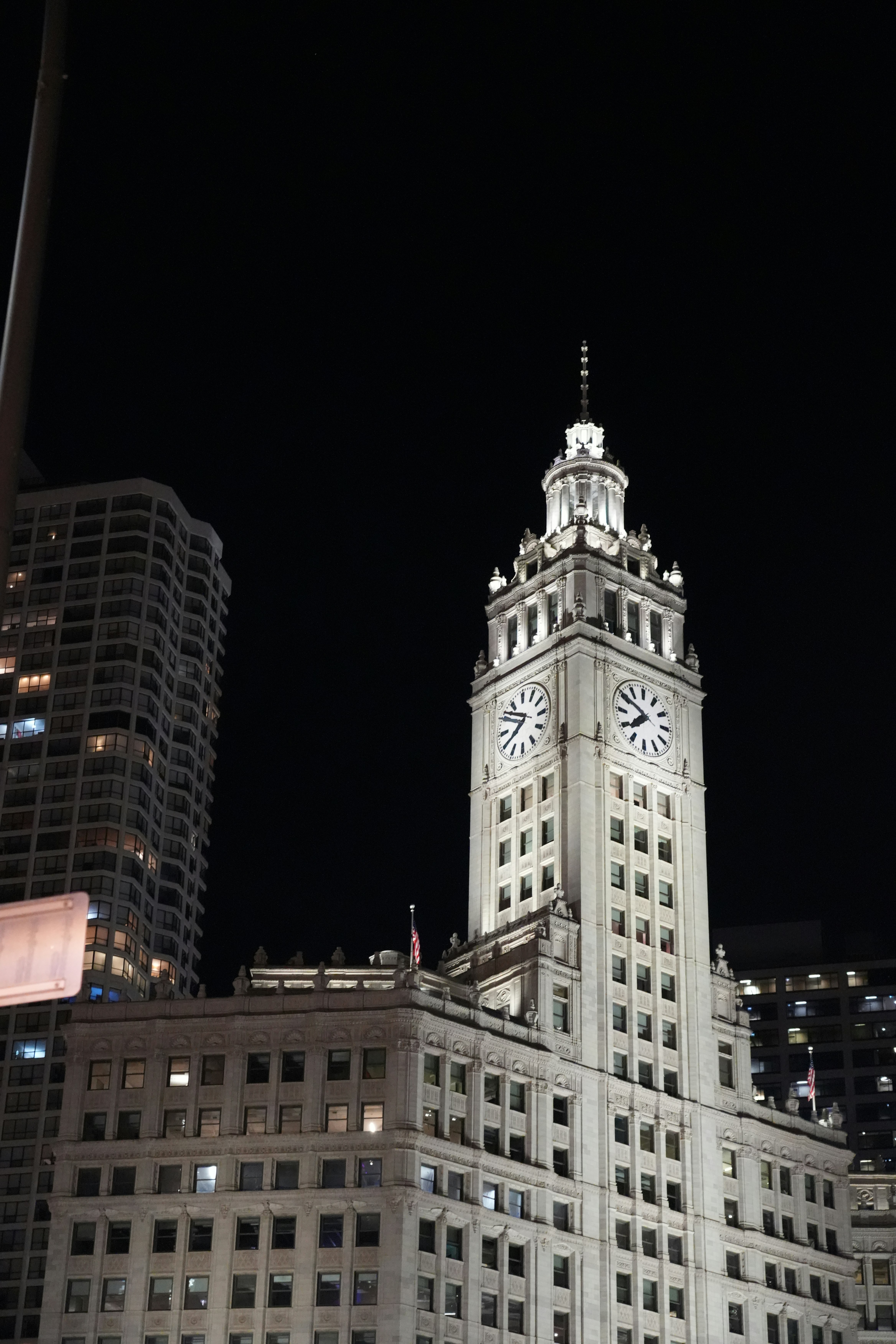 A tall white clock tower building at night.