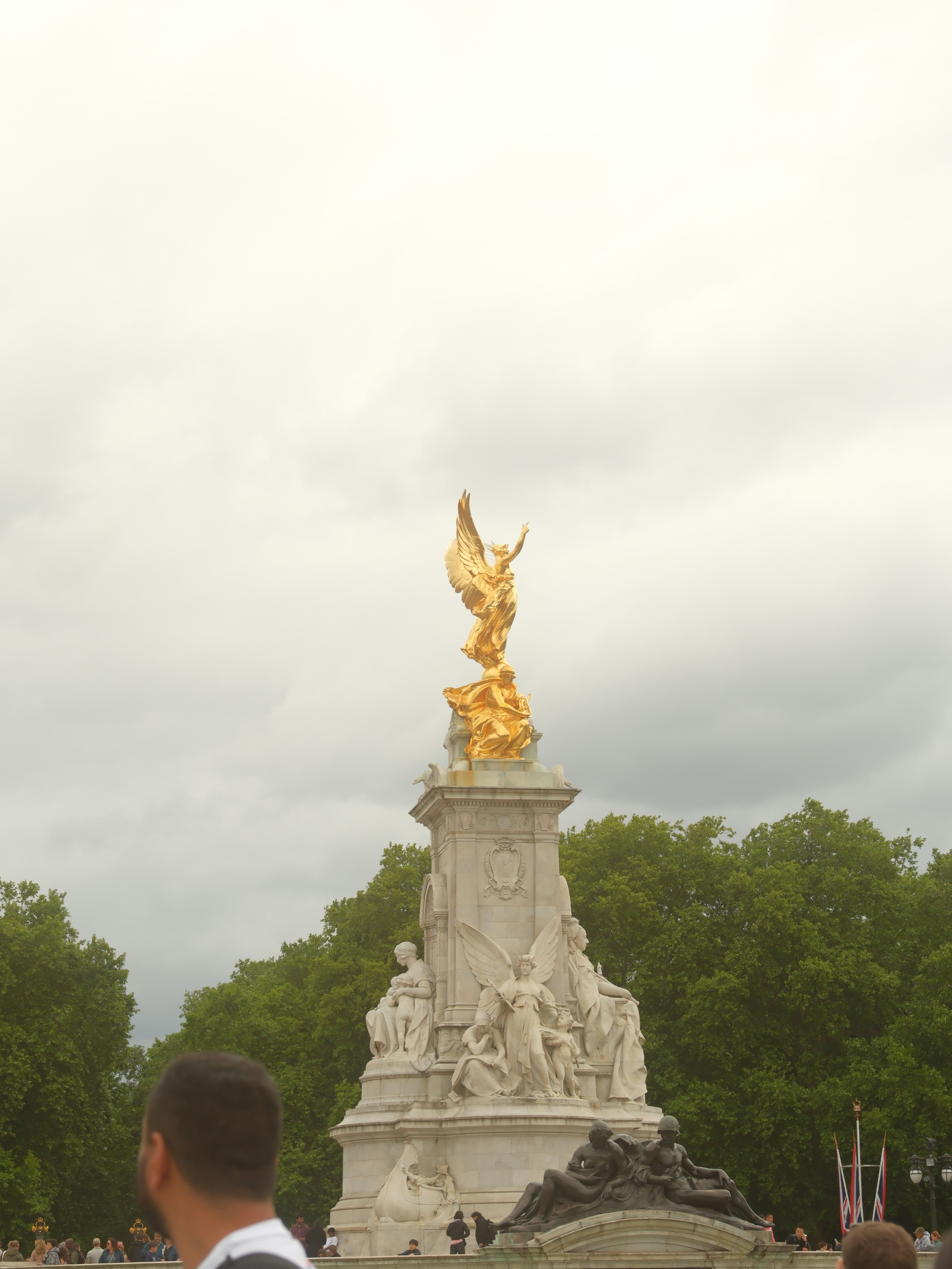 Golden statue atop a monument with trees behind