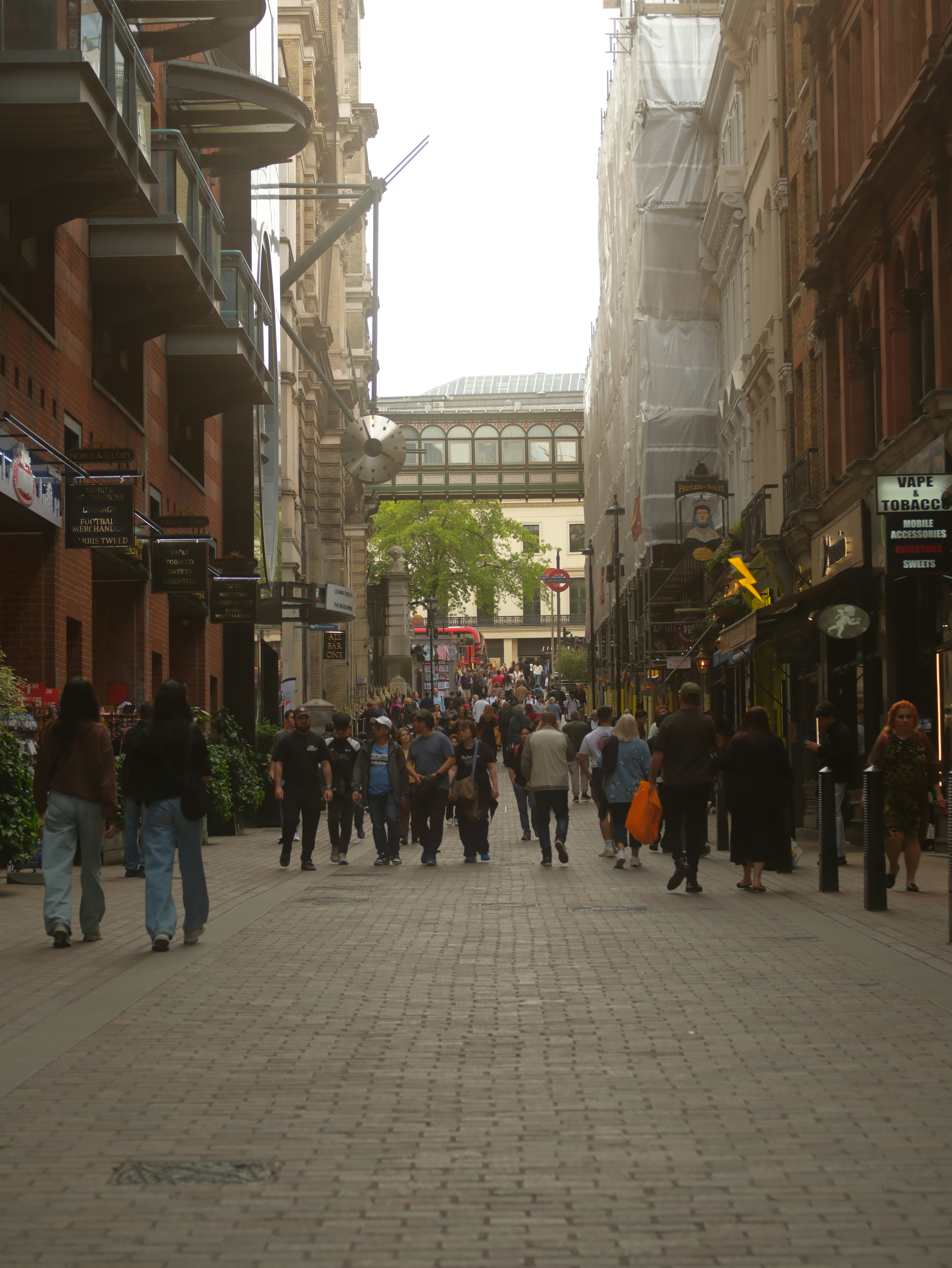 People walking down a cobblestone street in a city.