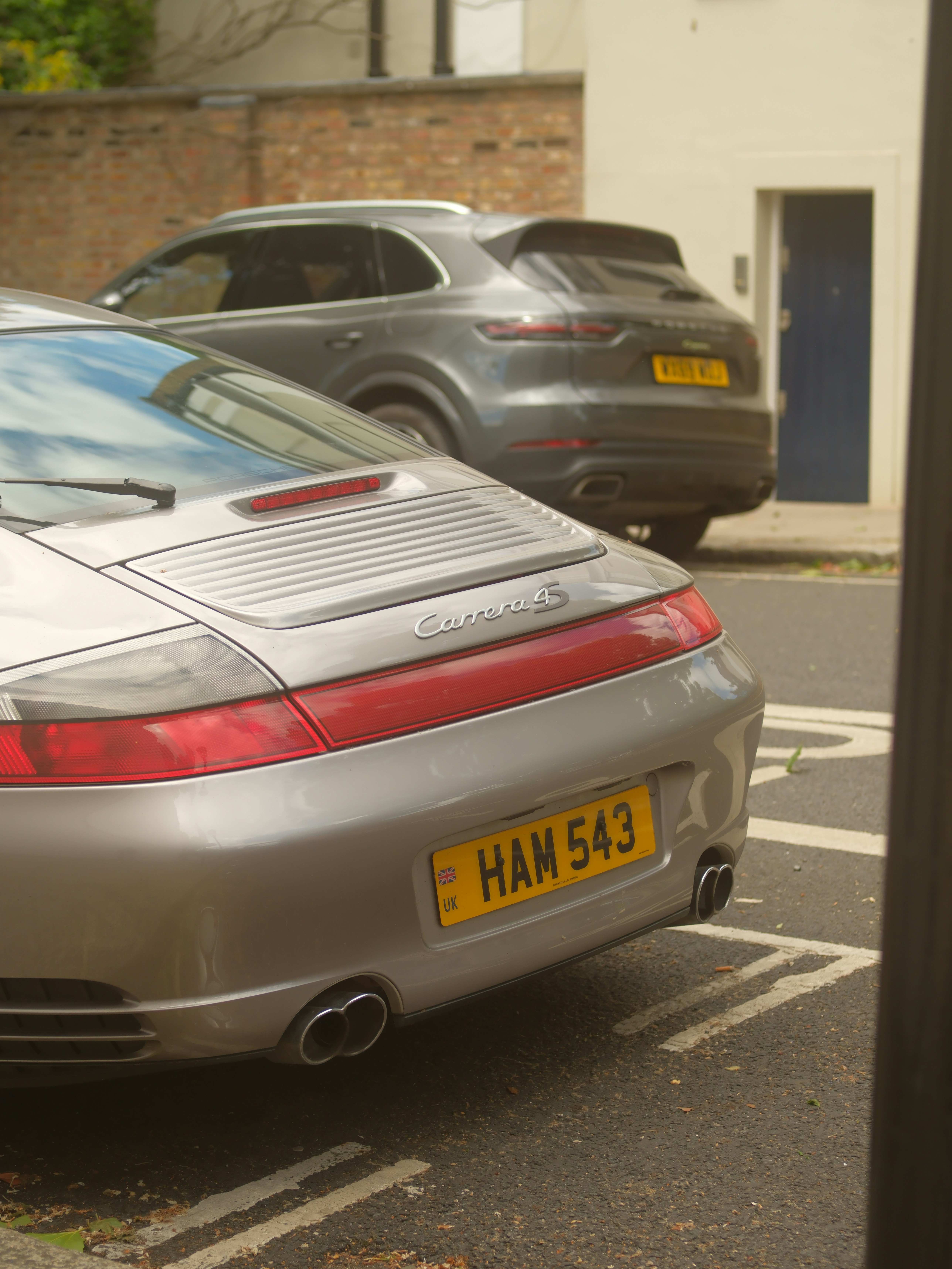 Silver porsche carrera s parked next to suv.