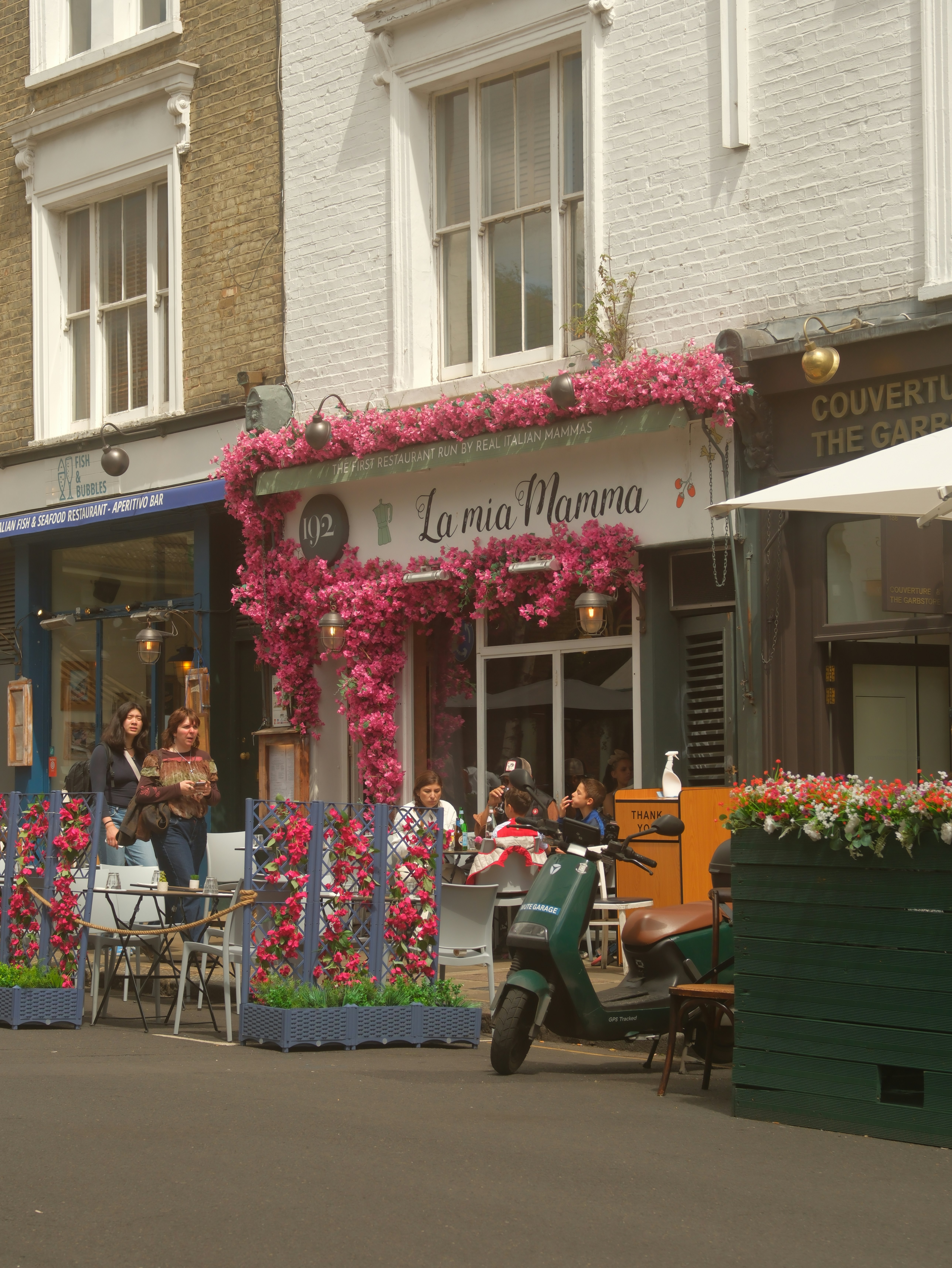 La Mia Mamma in Bloom: A Pink-Flowered Caféfront on a Bustling Street