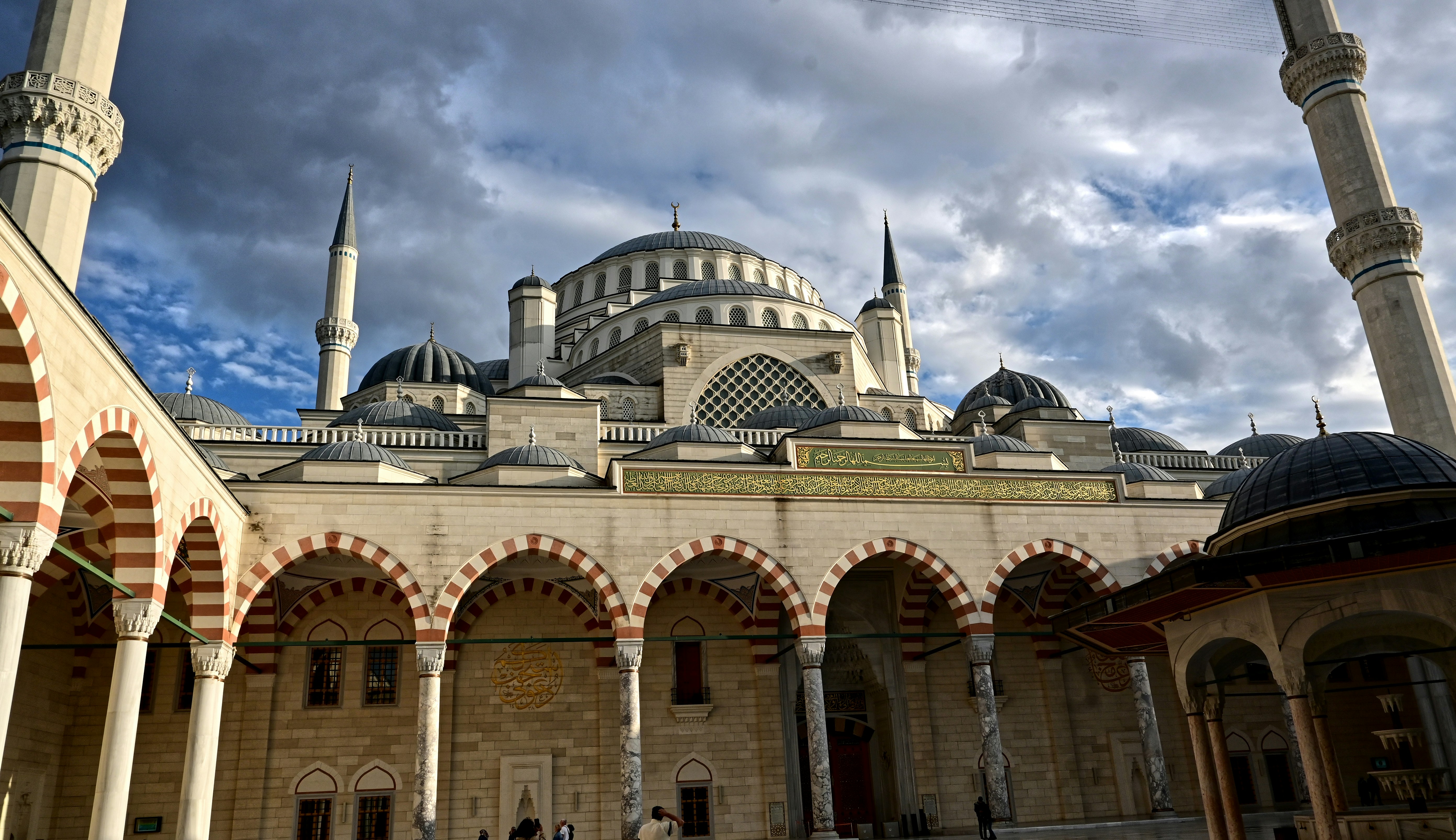 Majestic mosque with intricate arches and towering minarets under a dramatic sky.