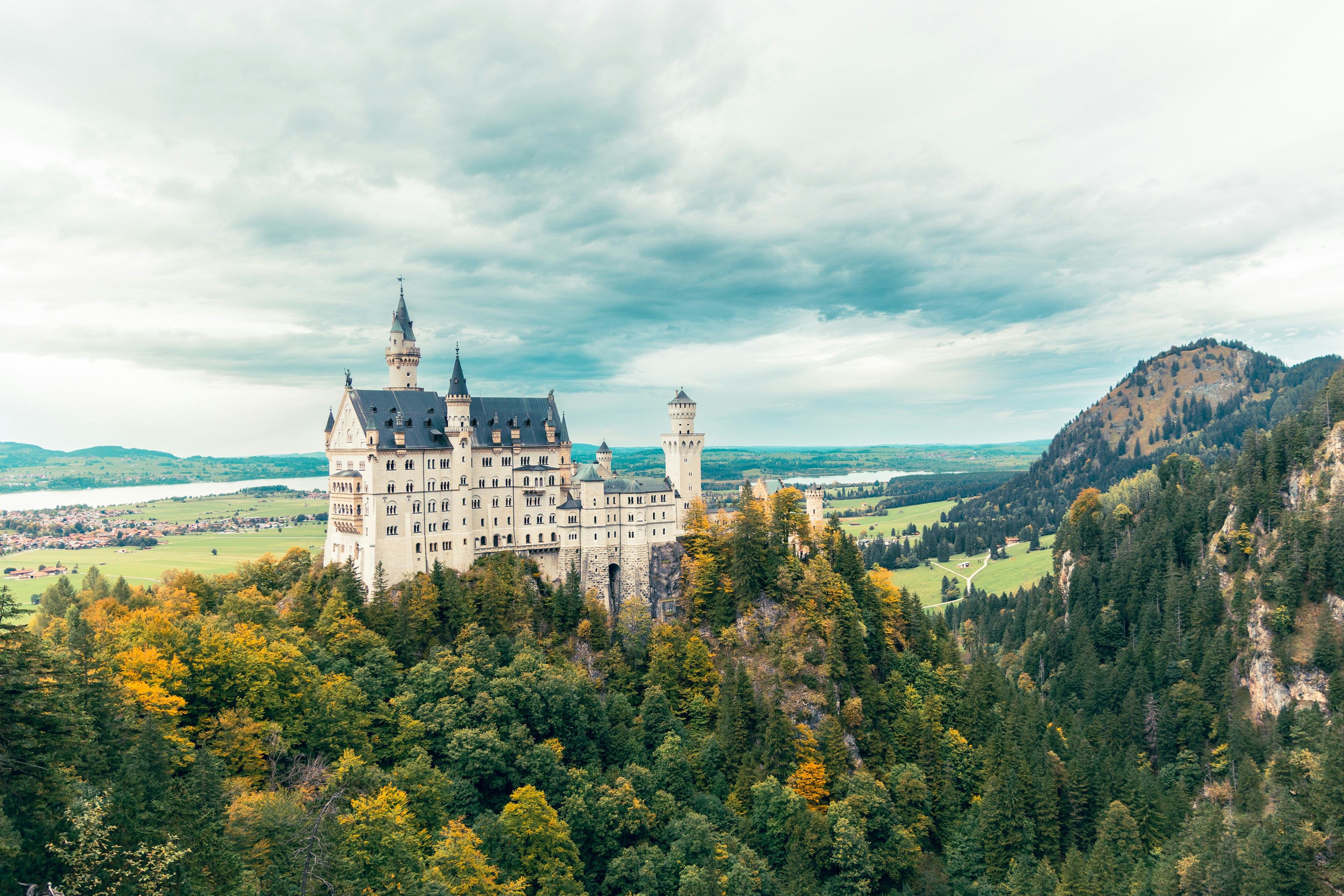 Neuschwanstein castle surrounded by autumn trees and mountains.