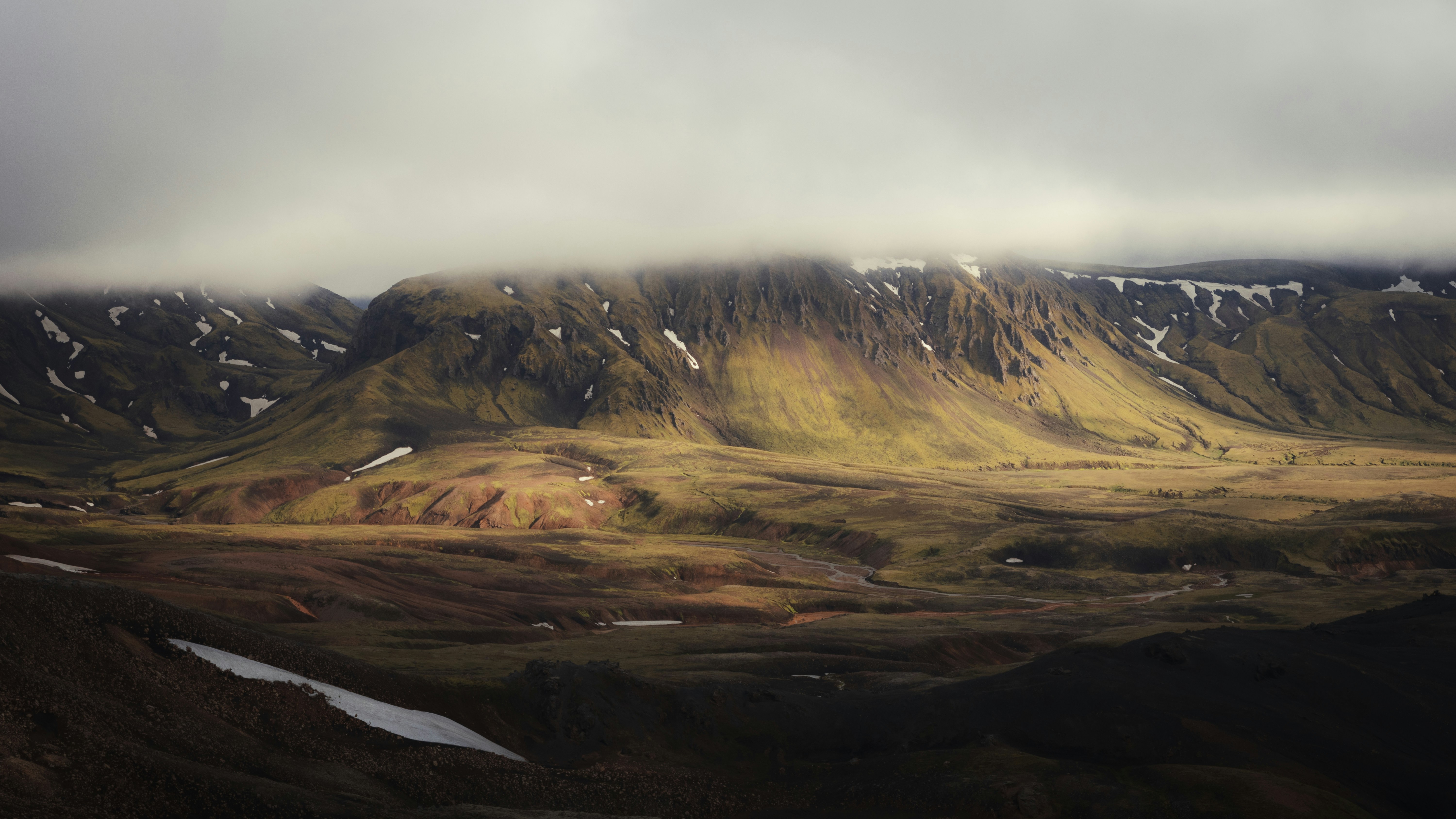 Misty mountains with patches of snow and sunlight.