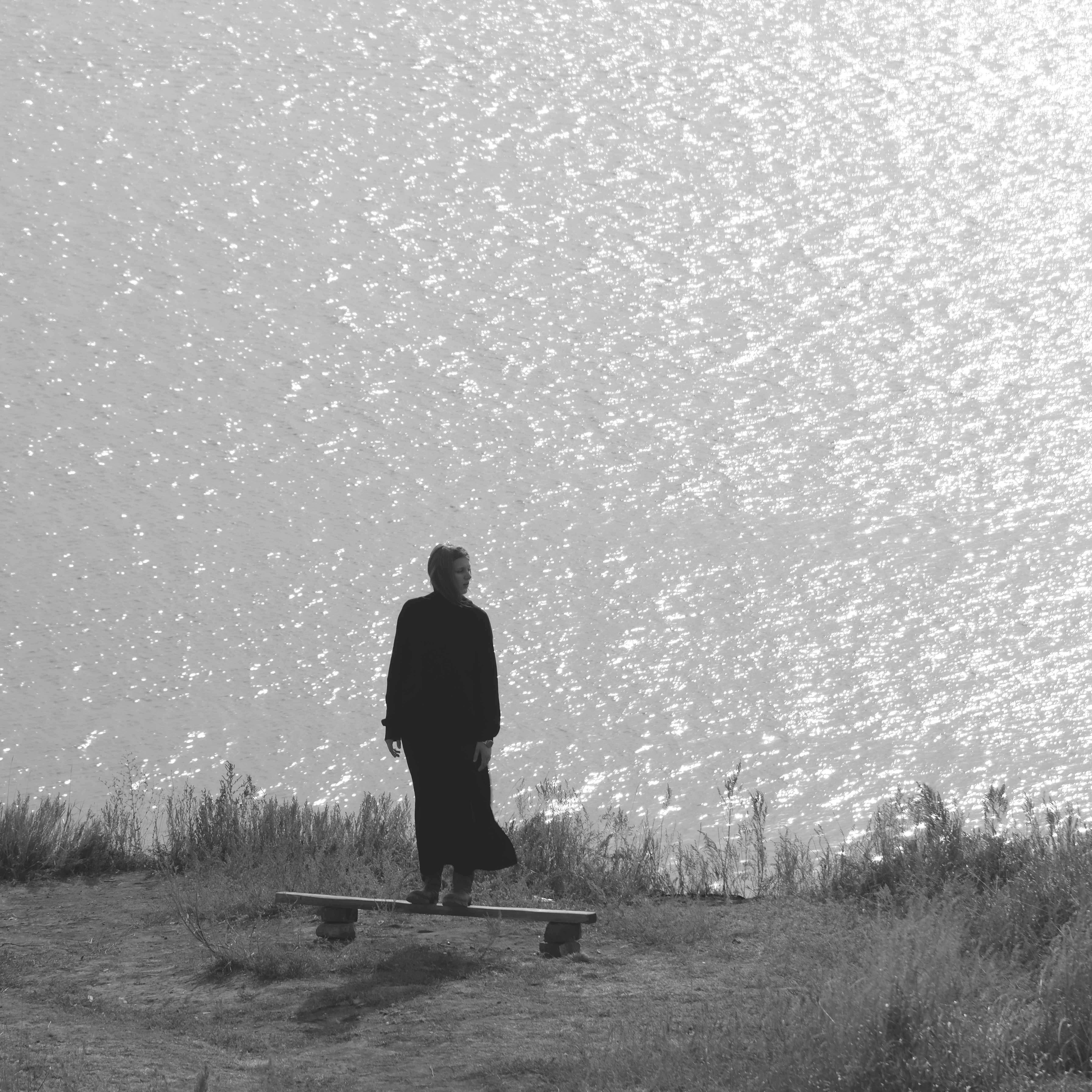 Person standing on bench overlooking sparkling water