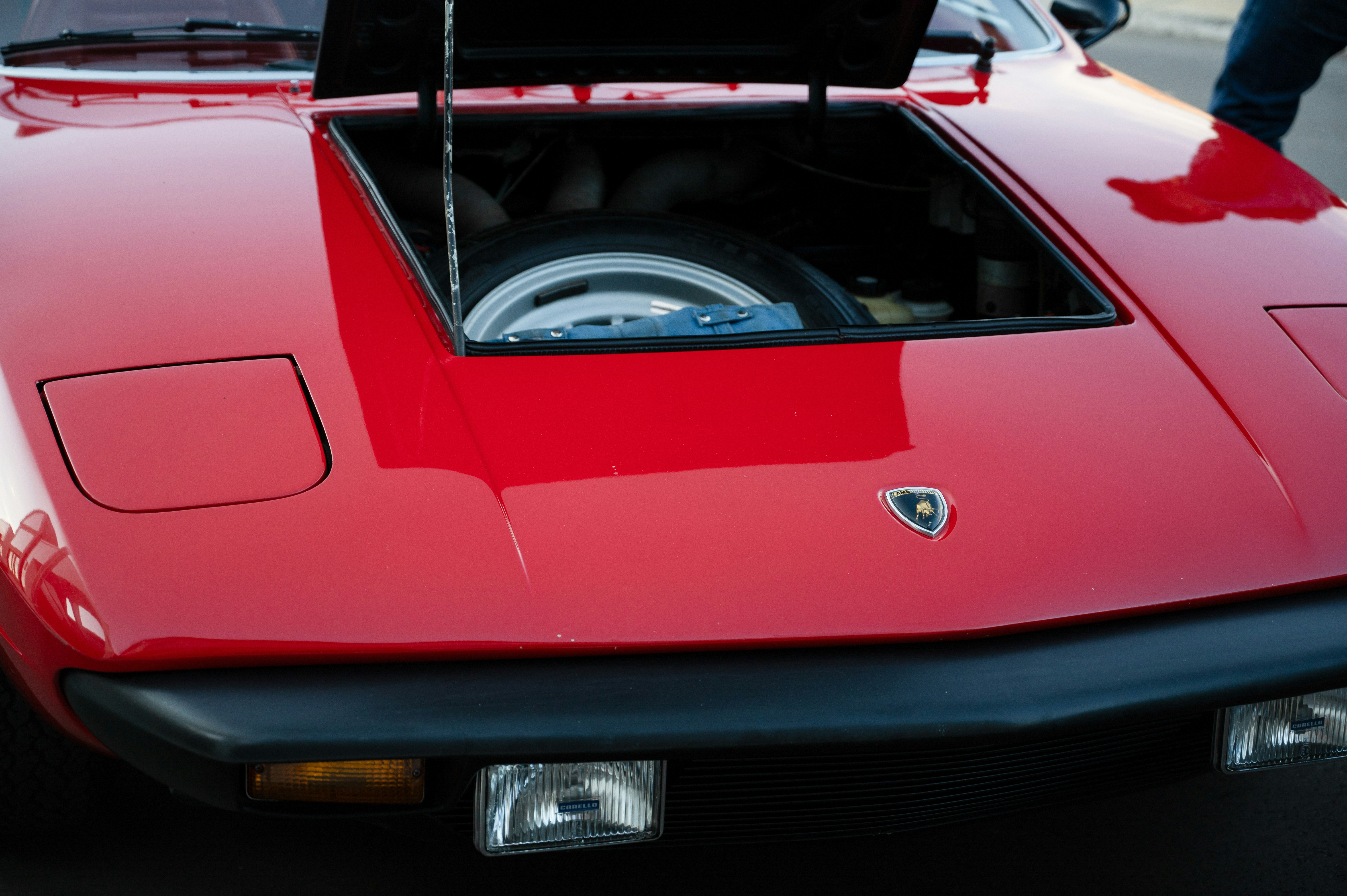 Red sports car with hood open showing spare tire