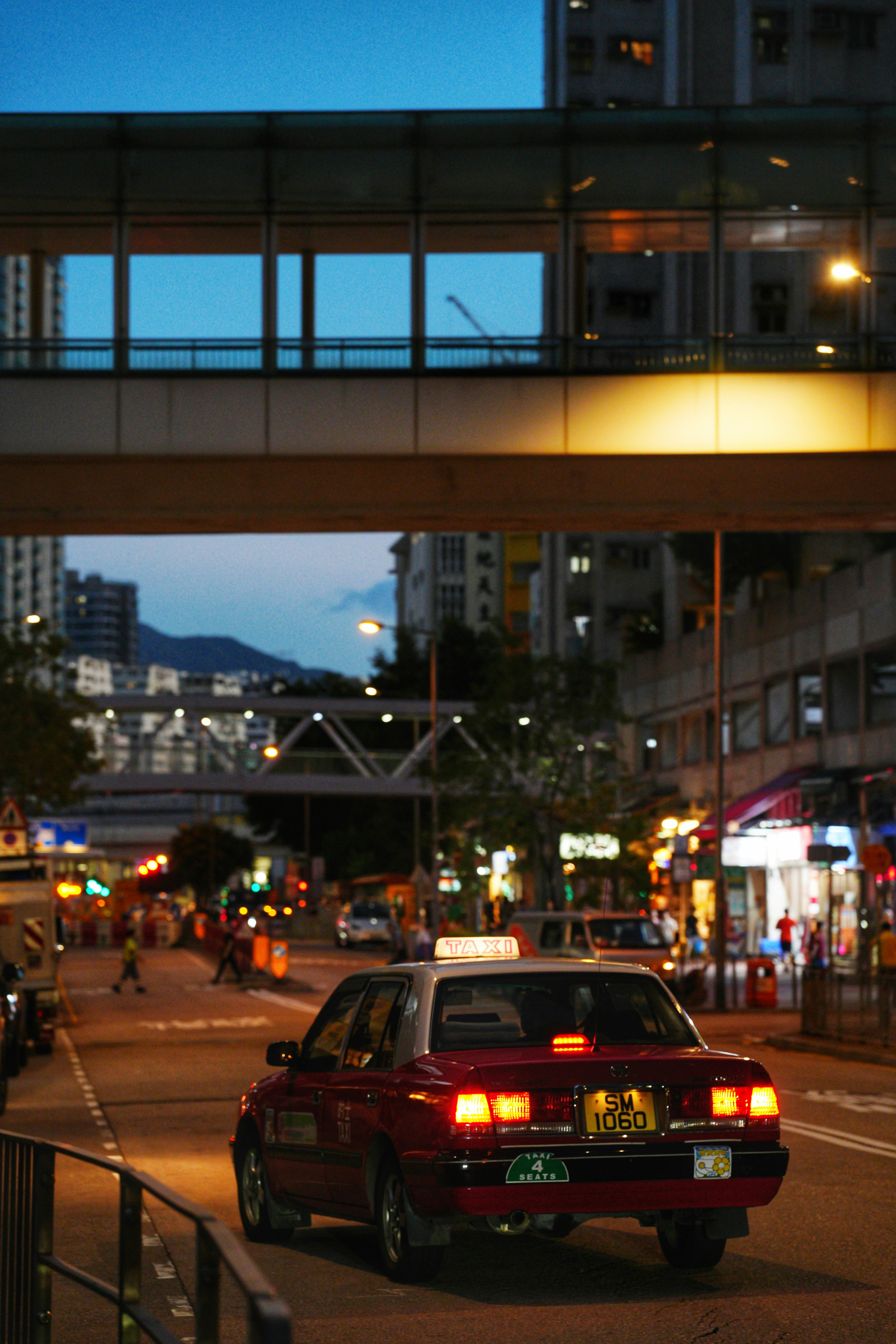 Red taxi drives down a busy city street at dusk. photo – Free Urban ...