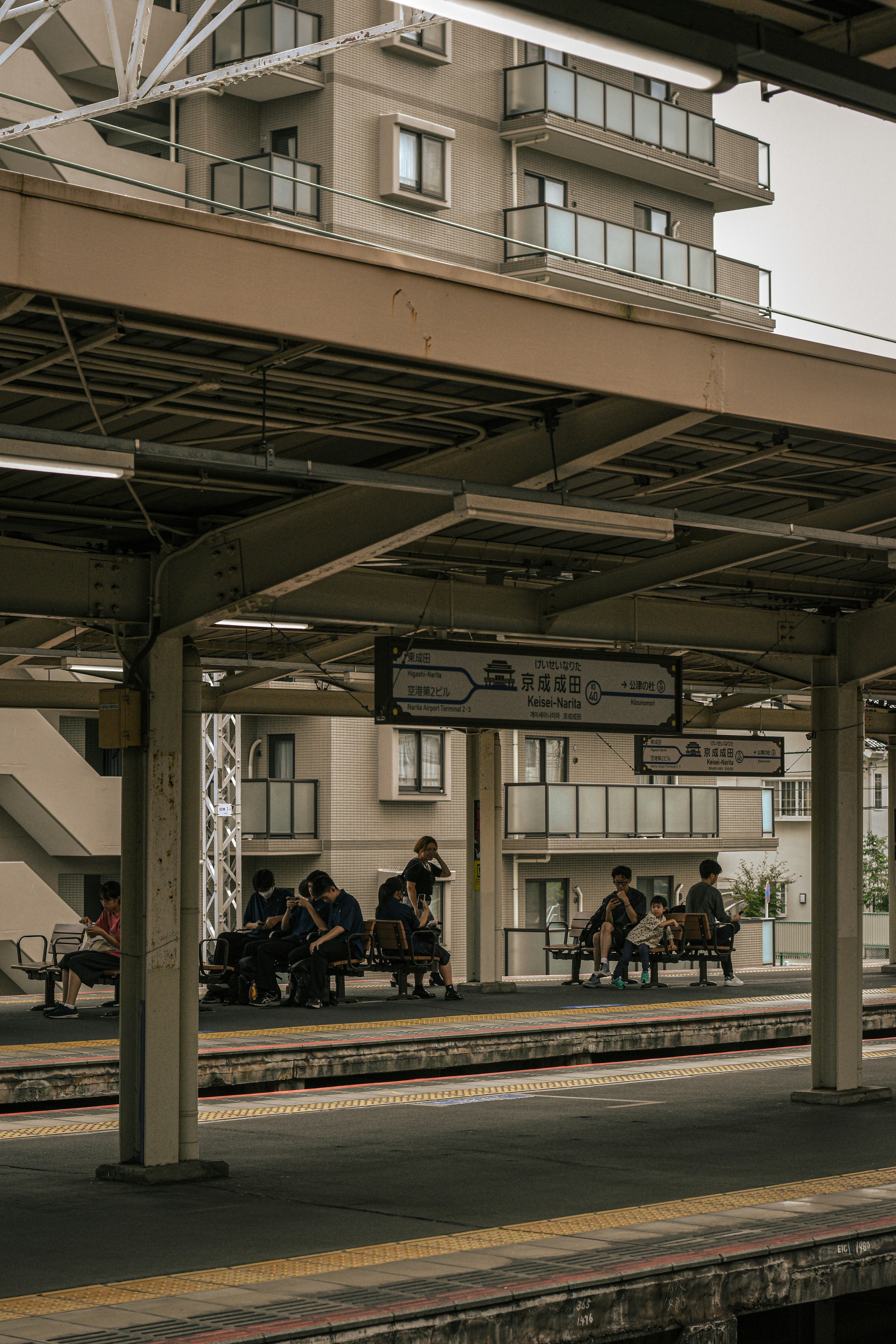 People waiting on a train platform under a shelter.