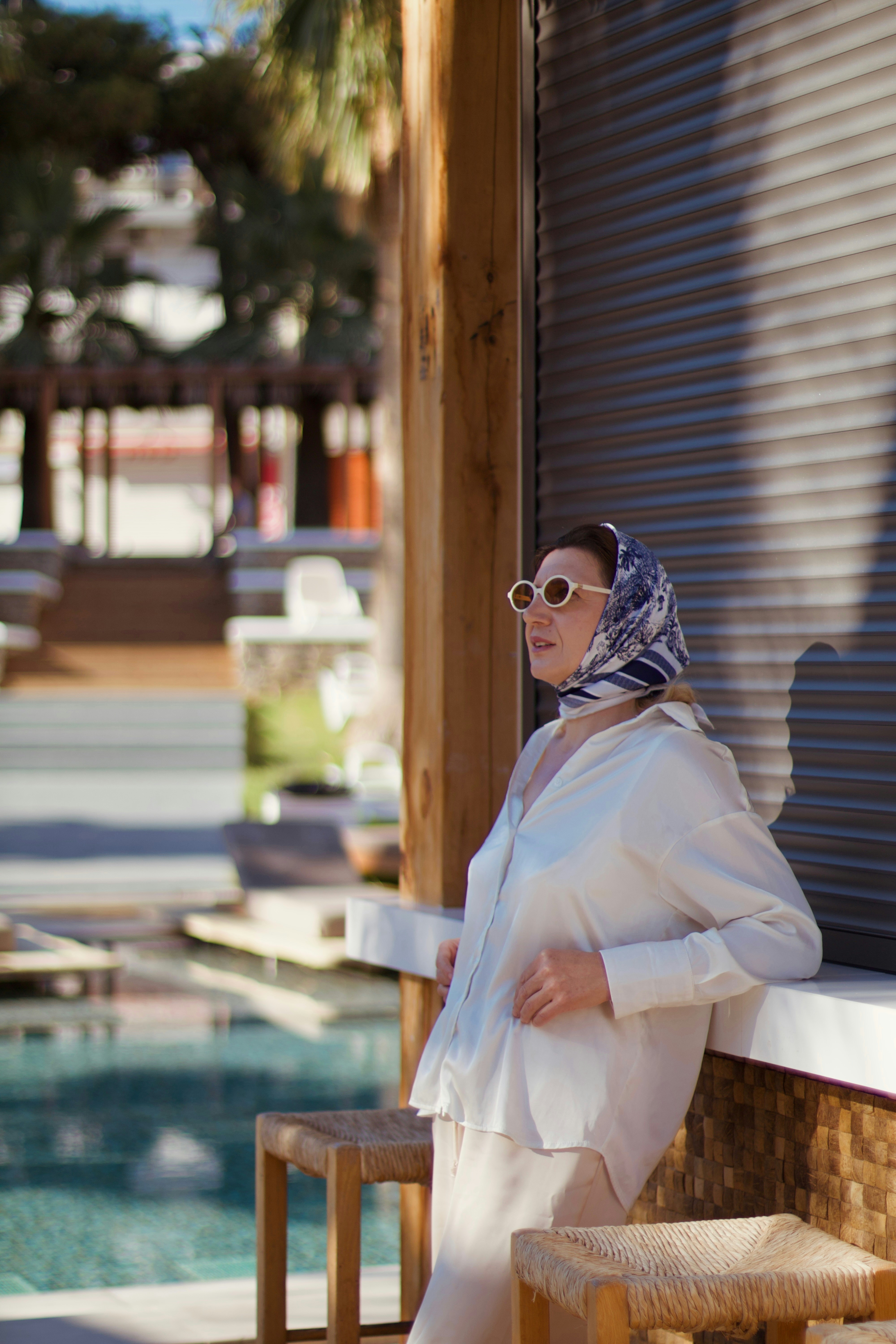 Woman in headscarf and sunglasses by pool