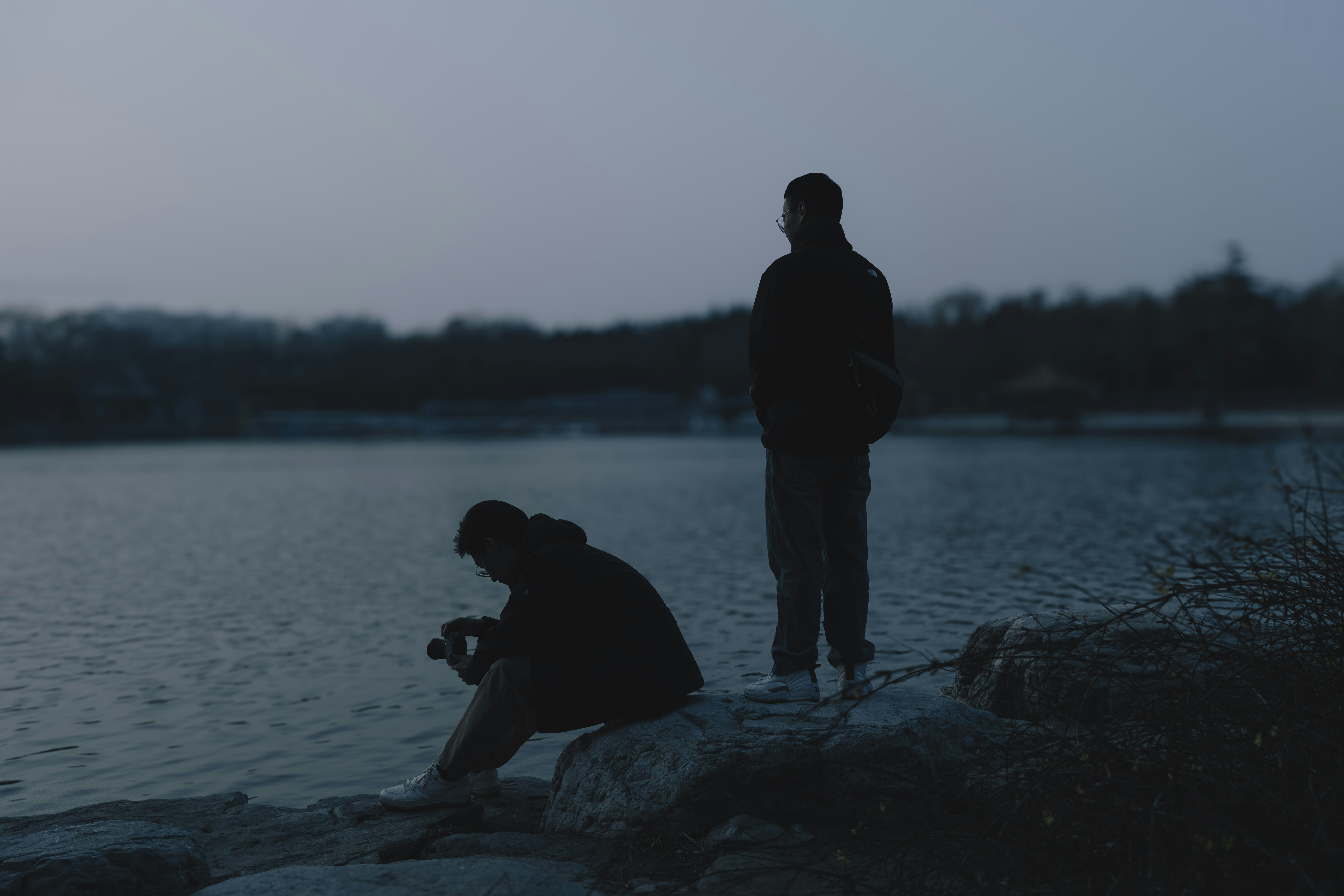 Two figures by a lake at dusk
