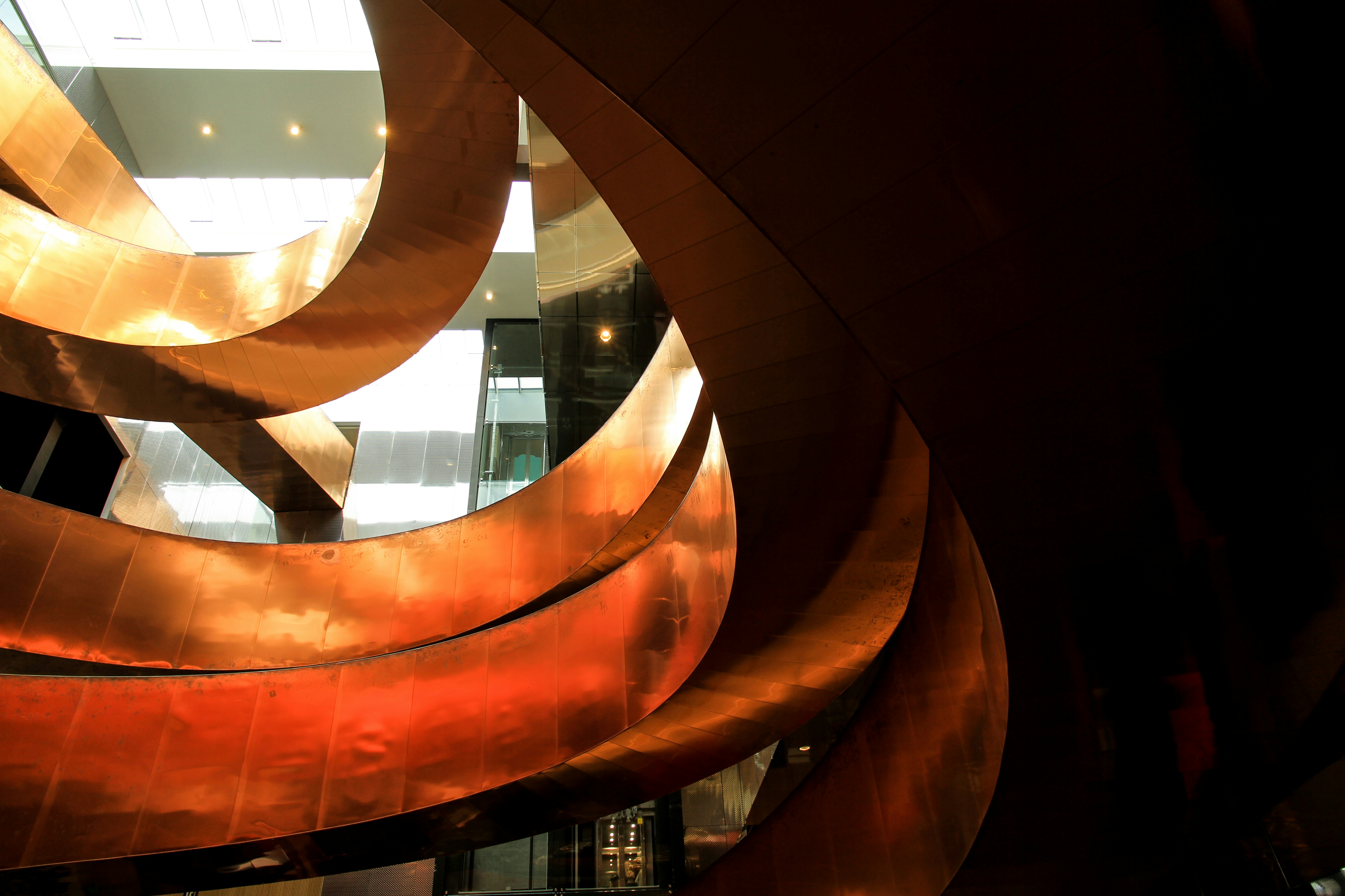 a twisting set of floating copper staircases at the main entrance of Copenhagen's new science and technology center | Abstract copper sculpture in a modern building