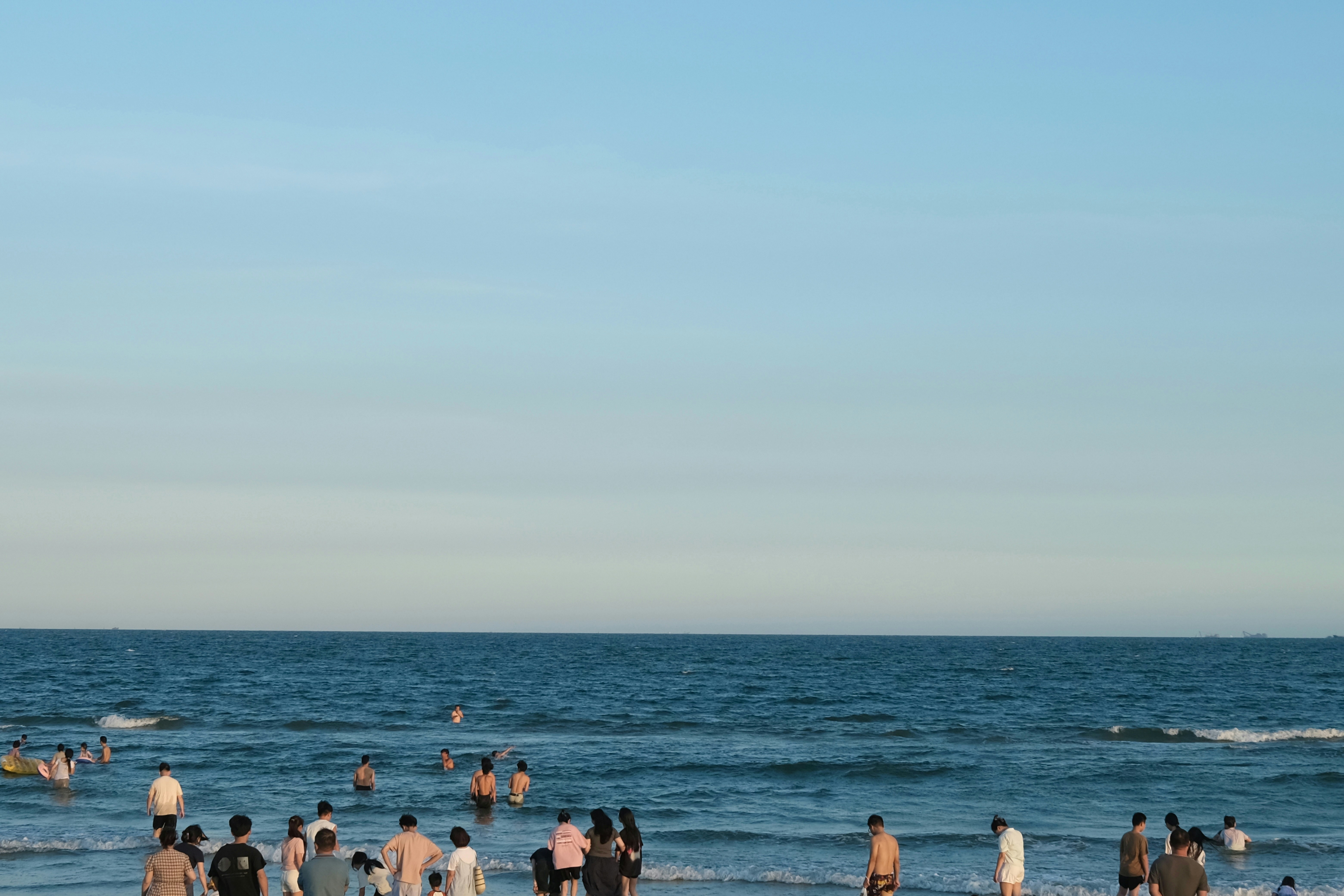 People wading in the ocean under a clear sky