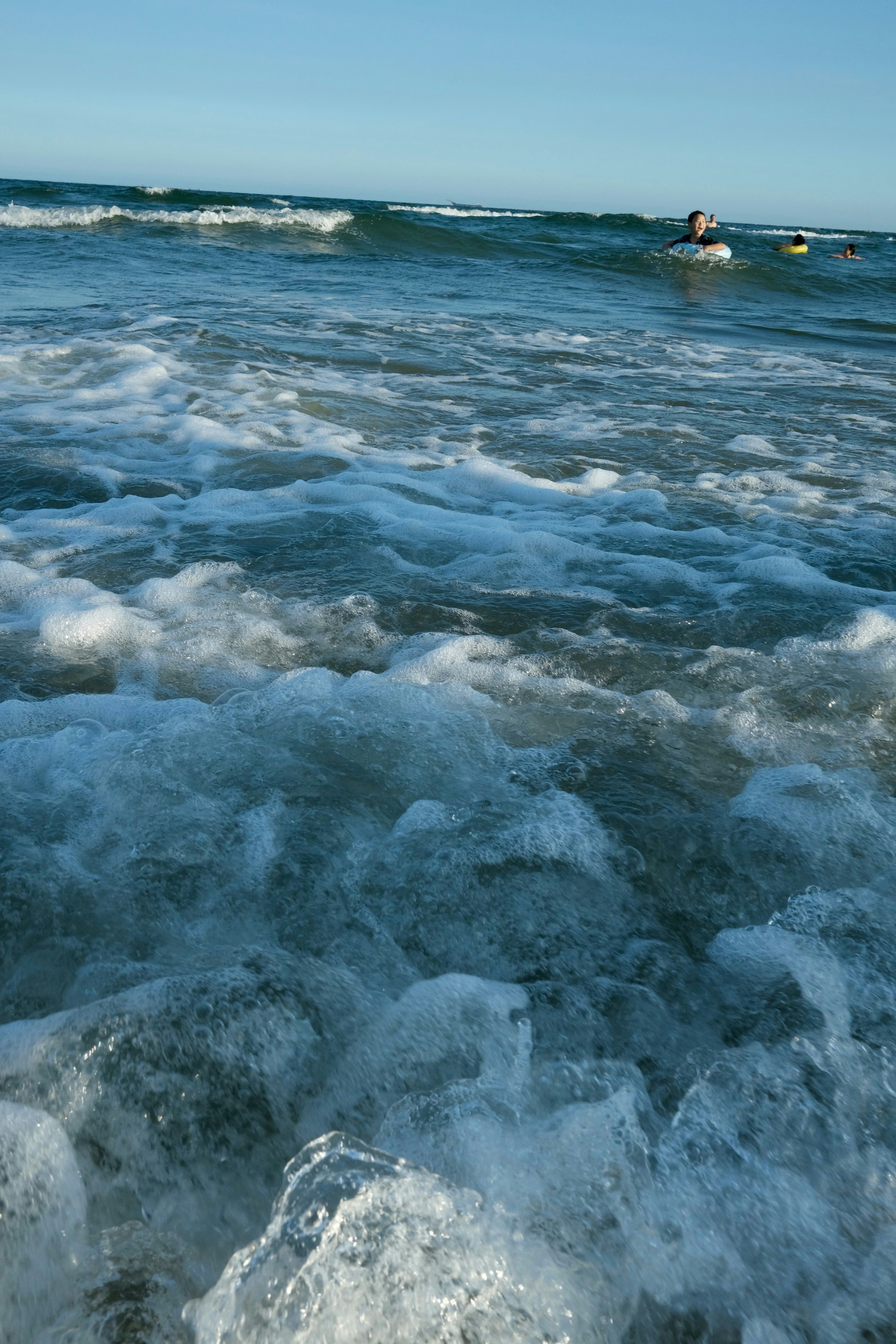 Waves crashing on a sandy beach with surfers