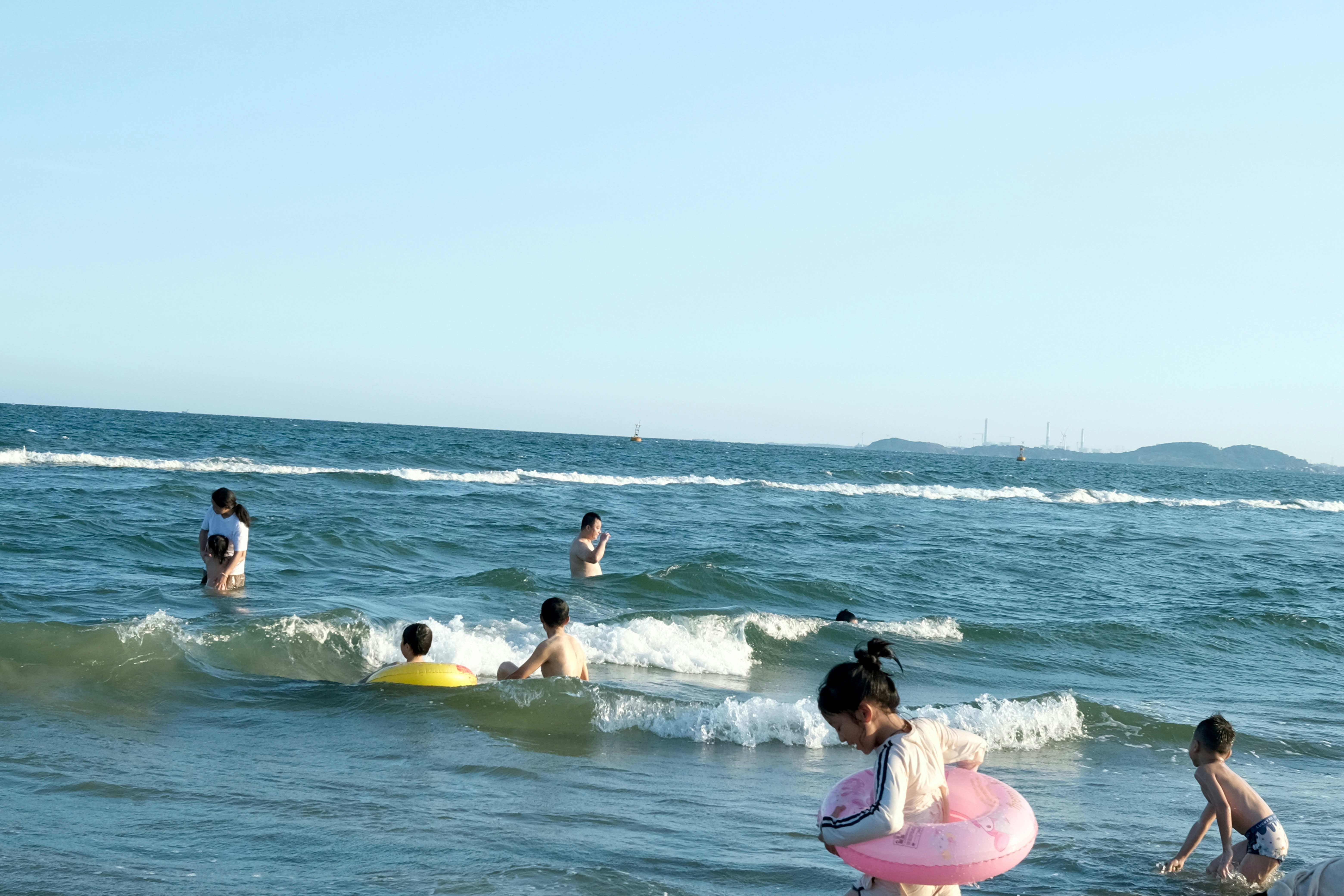 Children playing in the ocean waves on a sunny day.