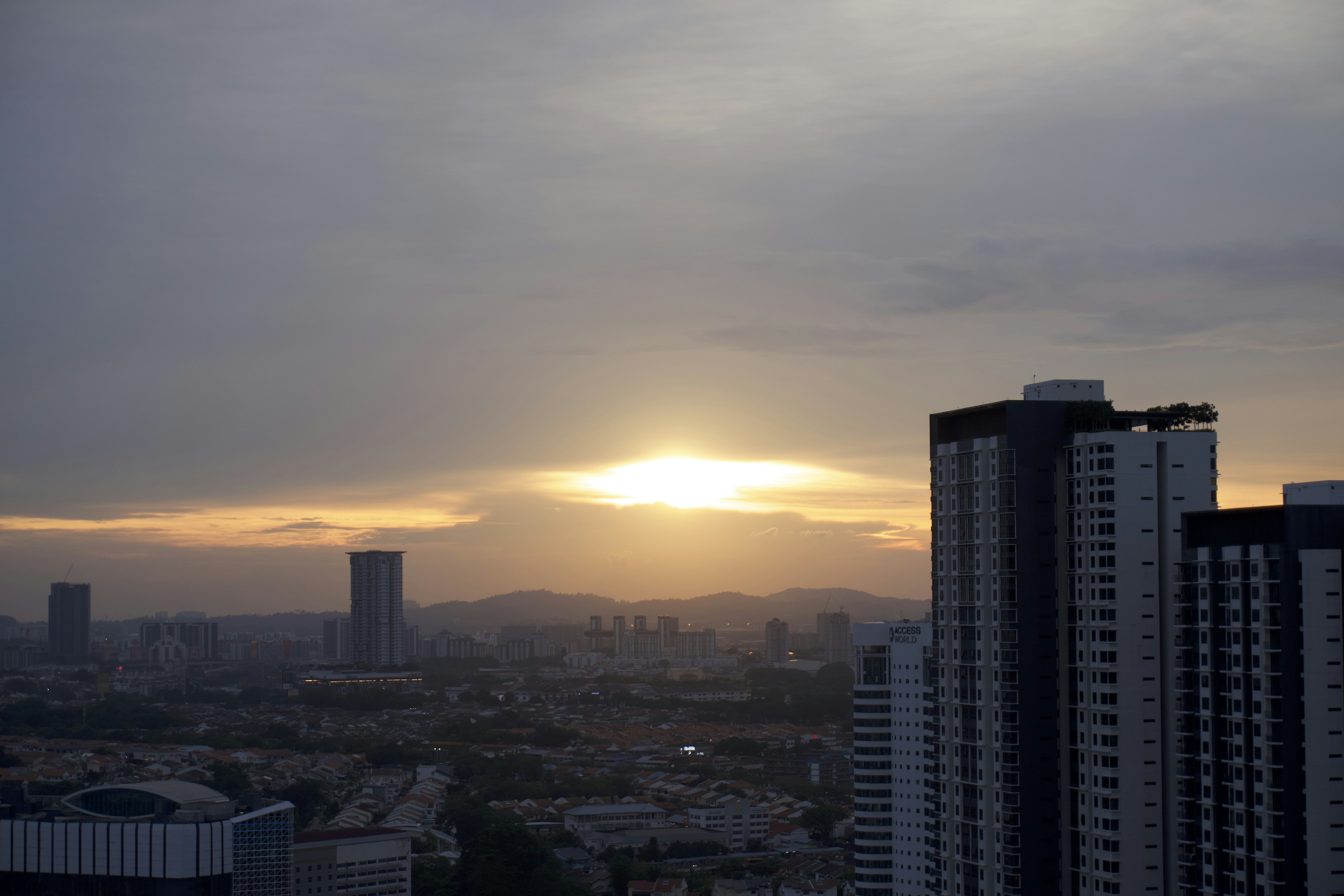 Sunset over a hazy cityscape with tall buildings.