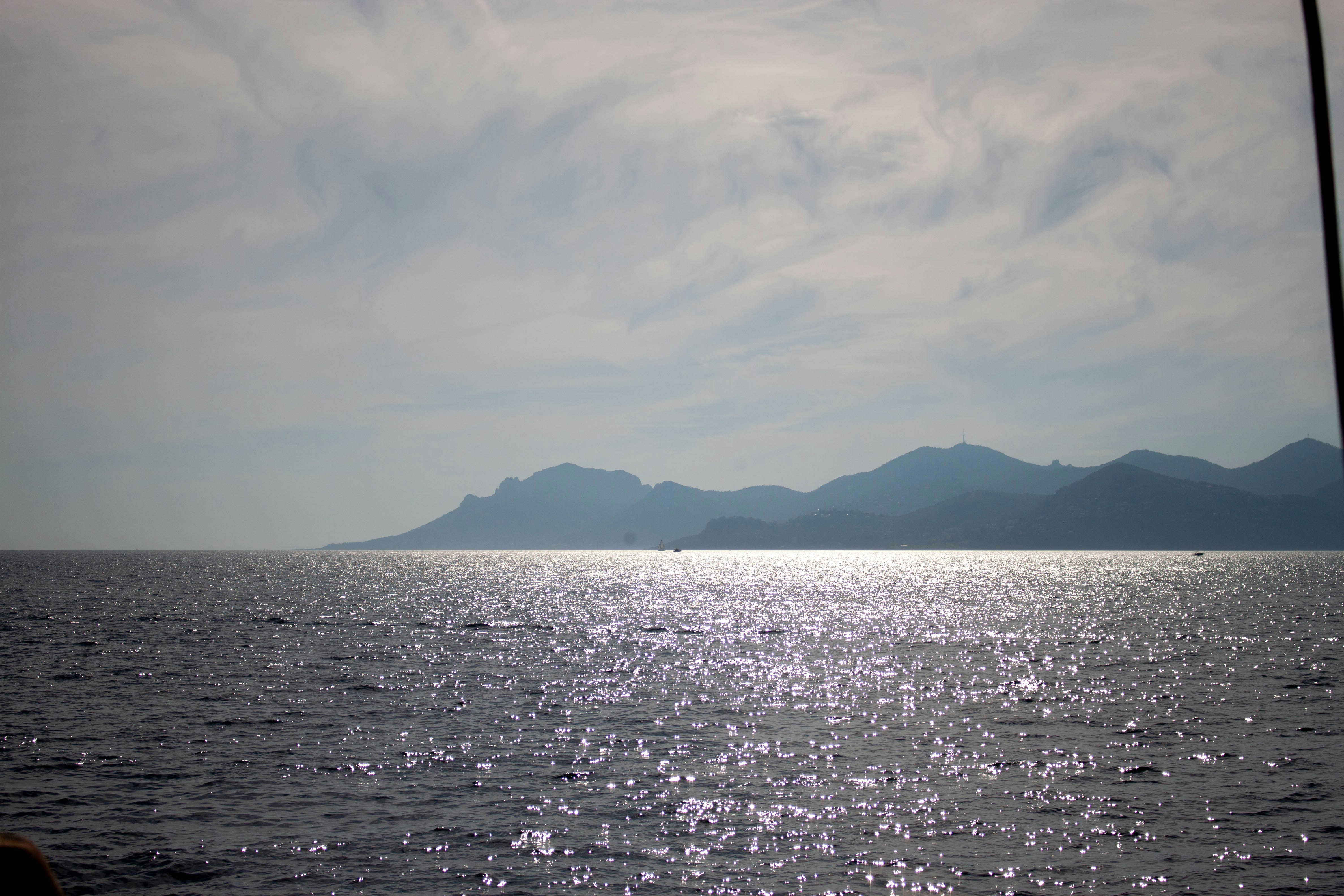 Sparkling ocean water with distant mountains under cloudy sky