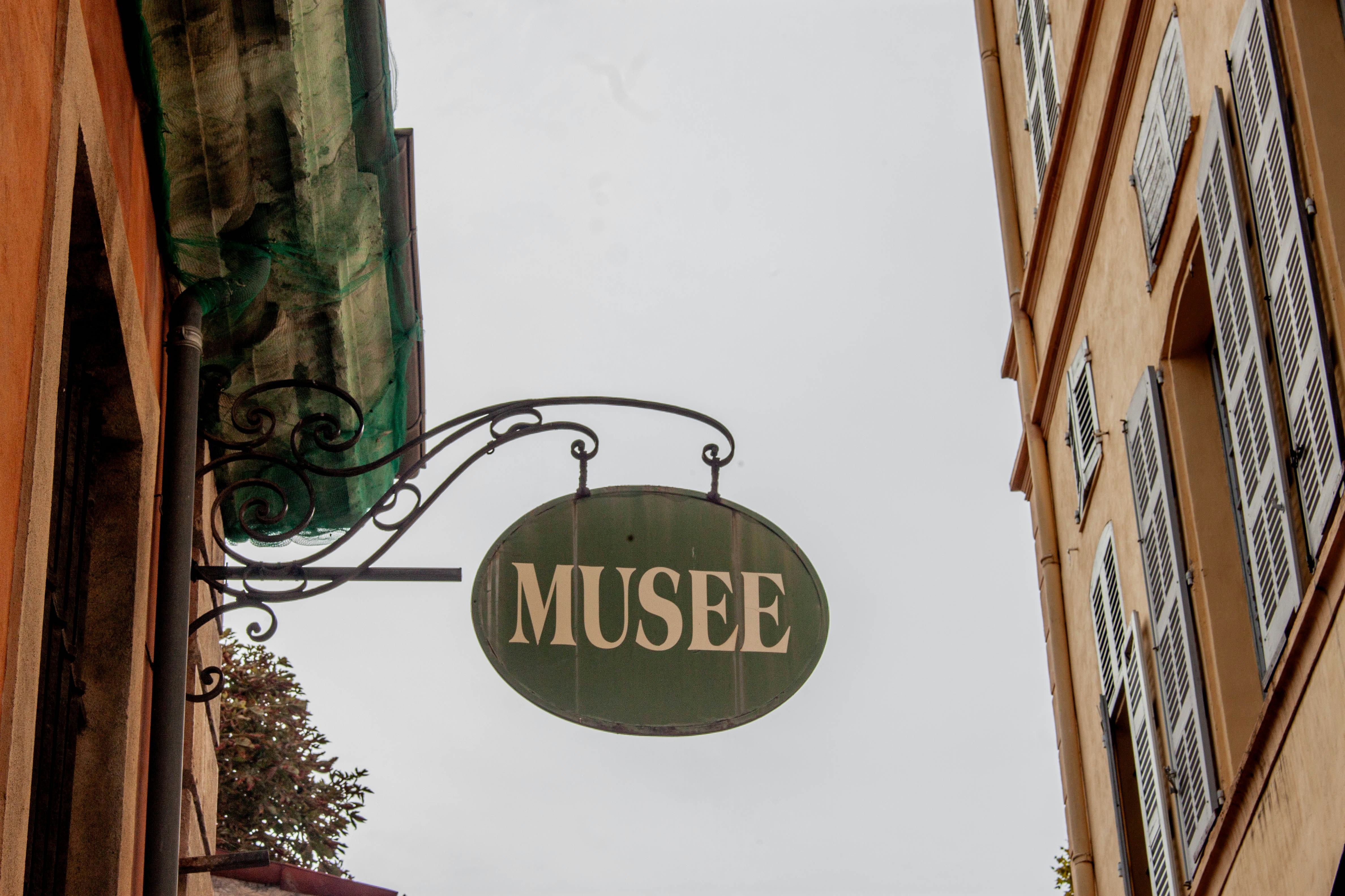 A sign reads musee hanging between buildings.