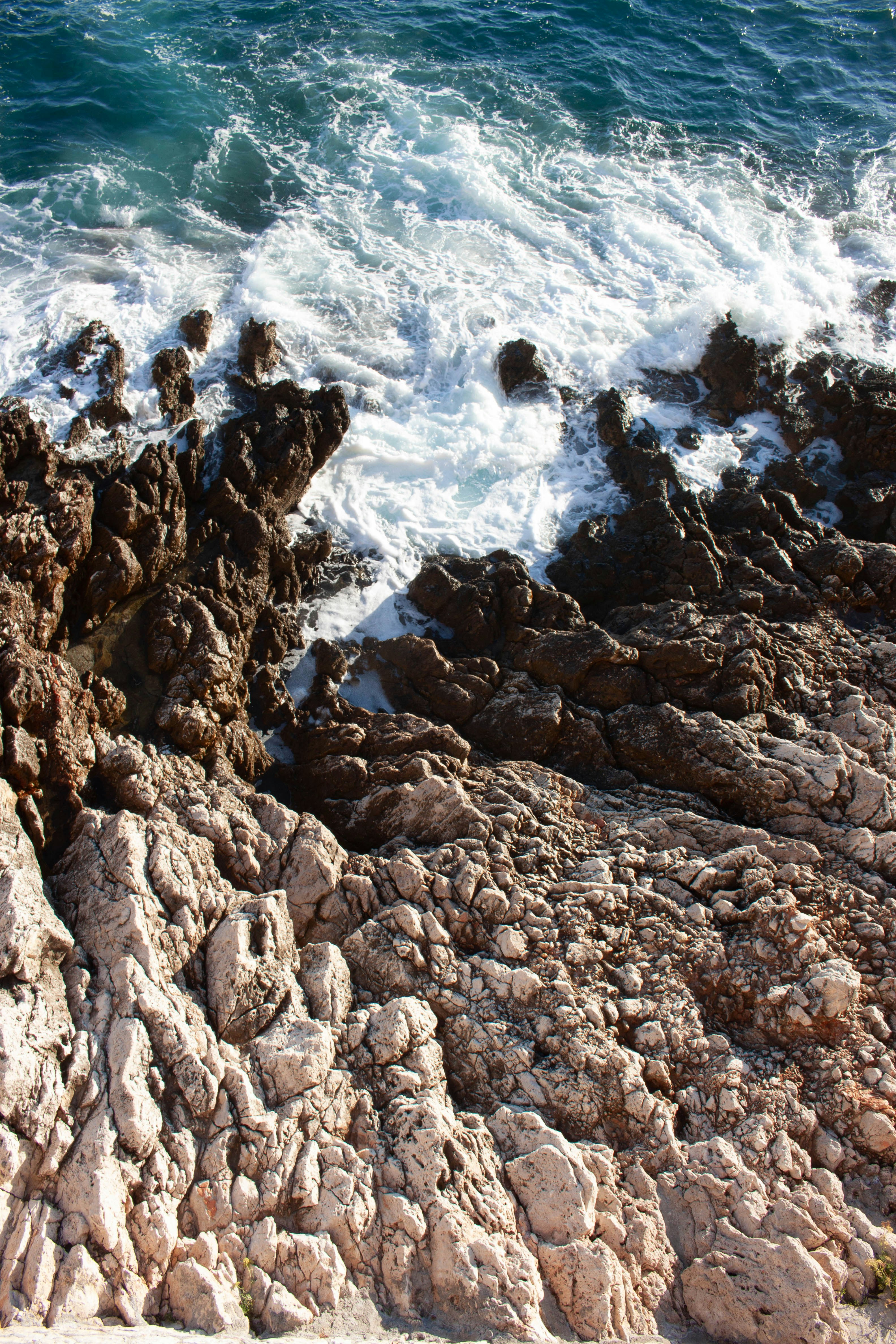 Rugged coastal rocks meet crashing waves, showcasing the dynamic interplay of land and sea. A natural landscape captured in vivid detail.