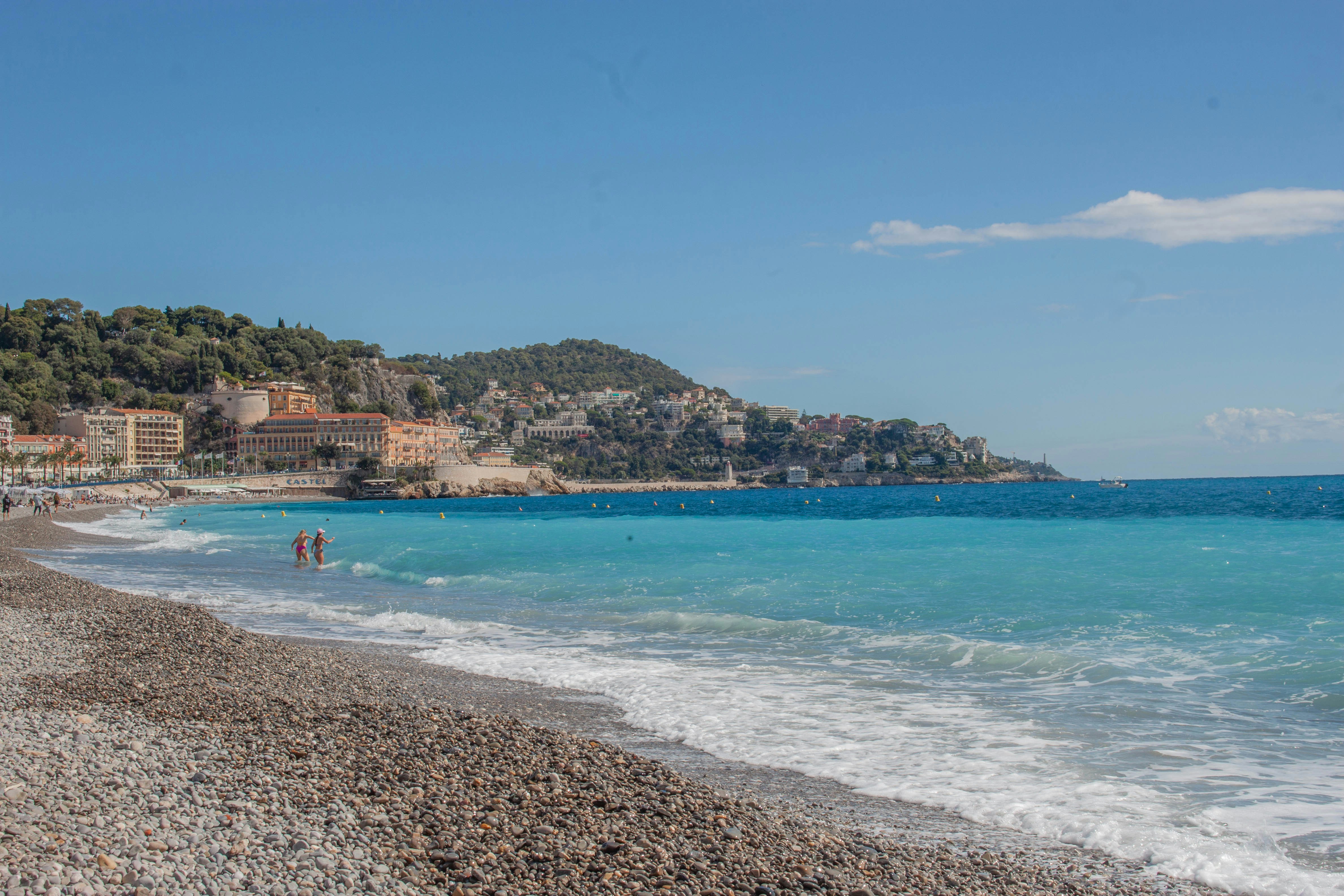 Pebble beach with turquoise water and coastal town. photo – Free Beach ...