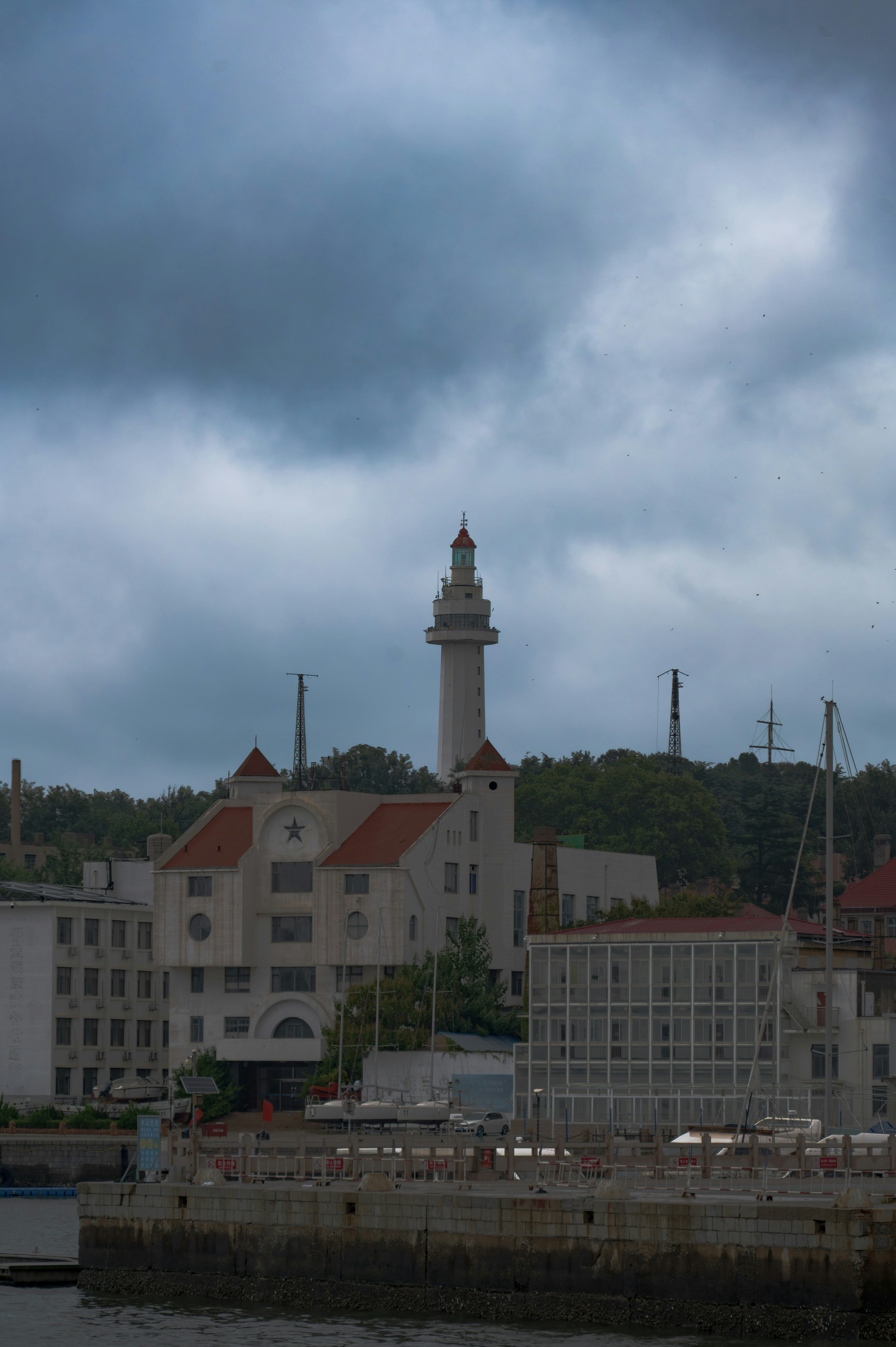 Lighthouse and buildings by the water under cloudy sky