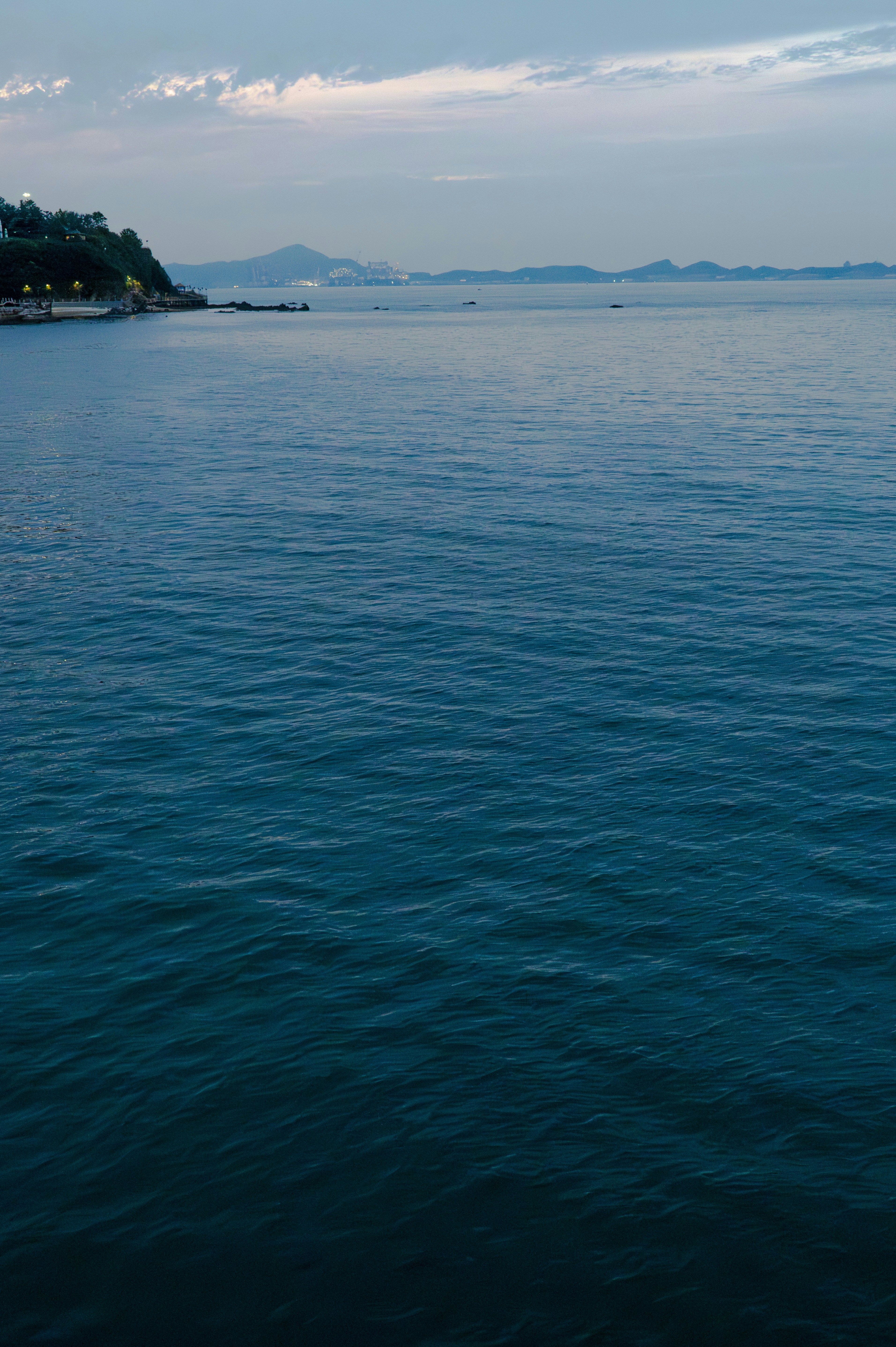 Calm blue ocean with distant islands under twilight sky
