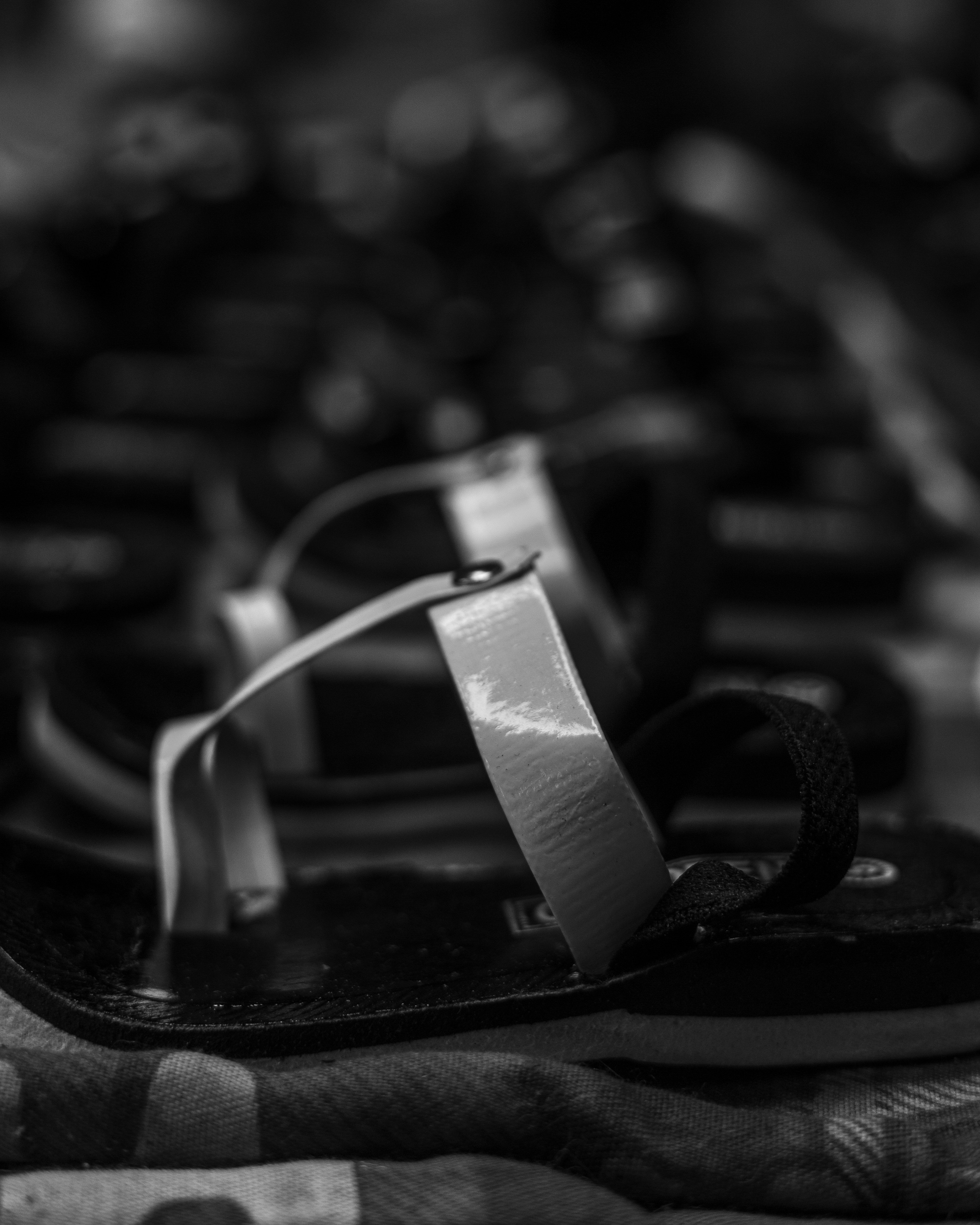 Black and white close-up of flip-flops resting on a textured surface, highlighting the interplay of light and shadow.